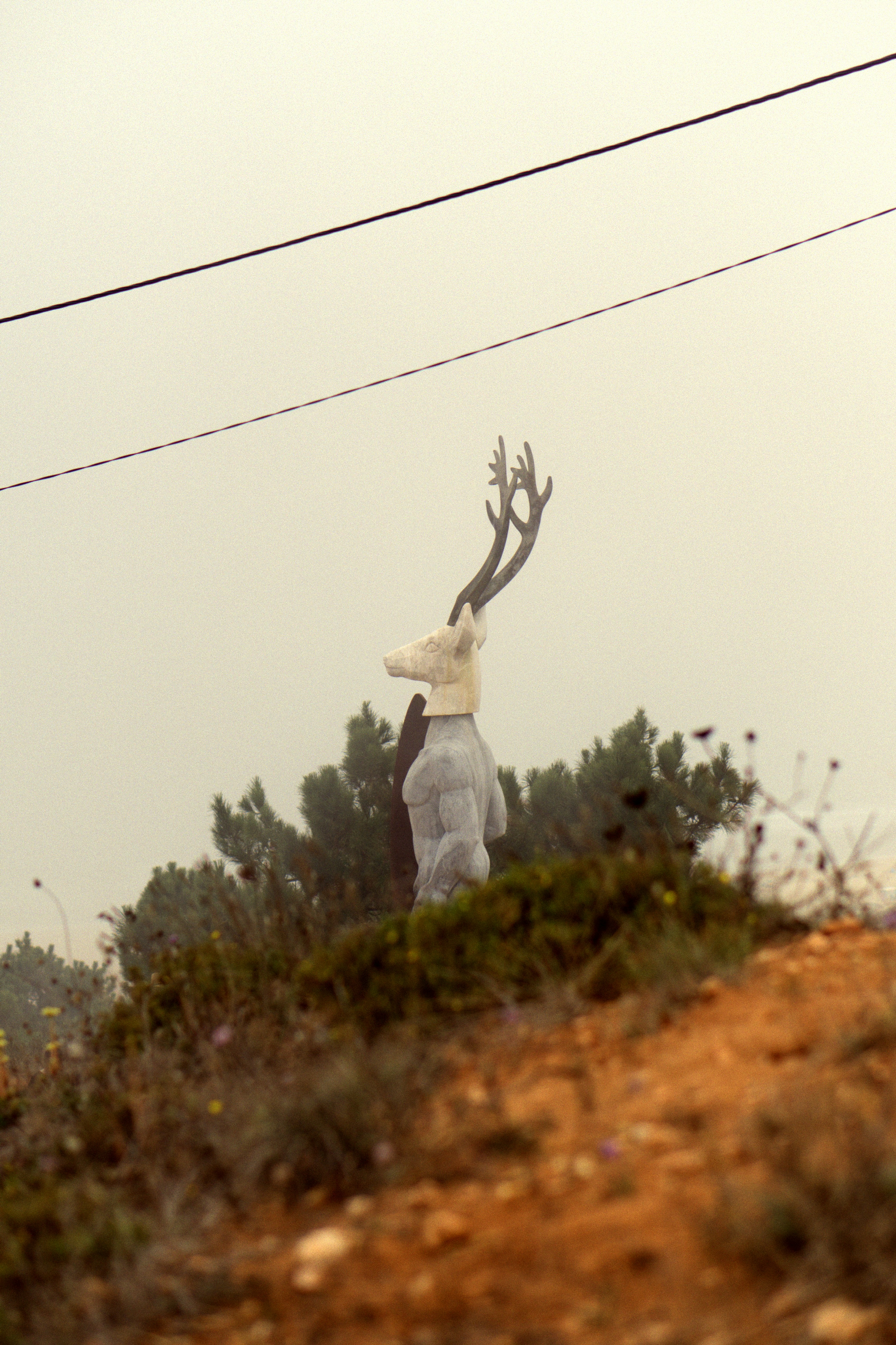 Stalking on the Ridge: A deer-headed figure watches over a barren slope