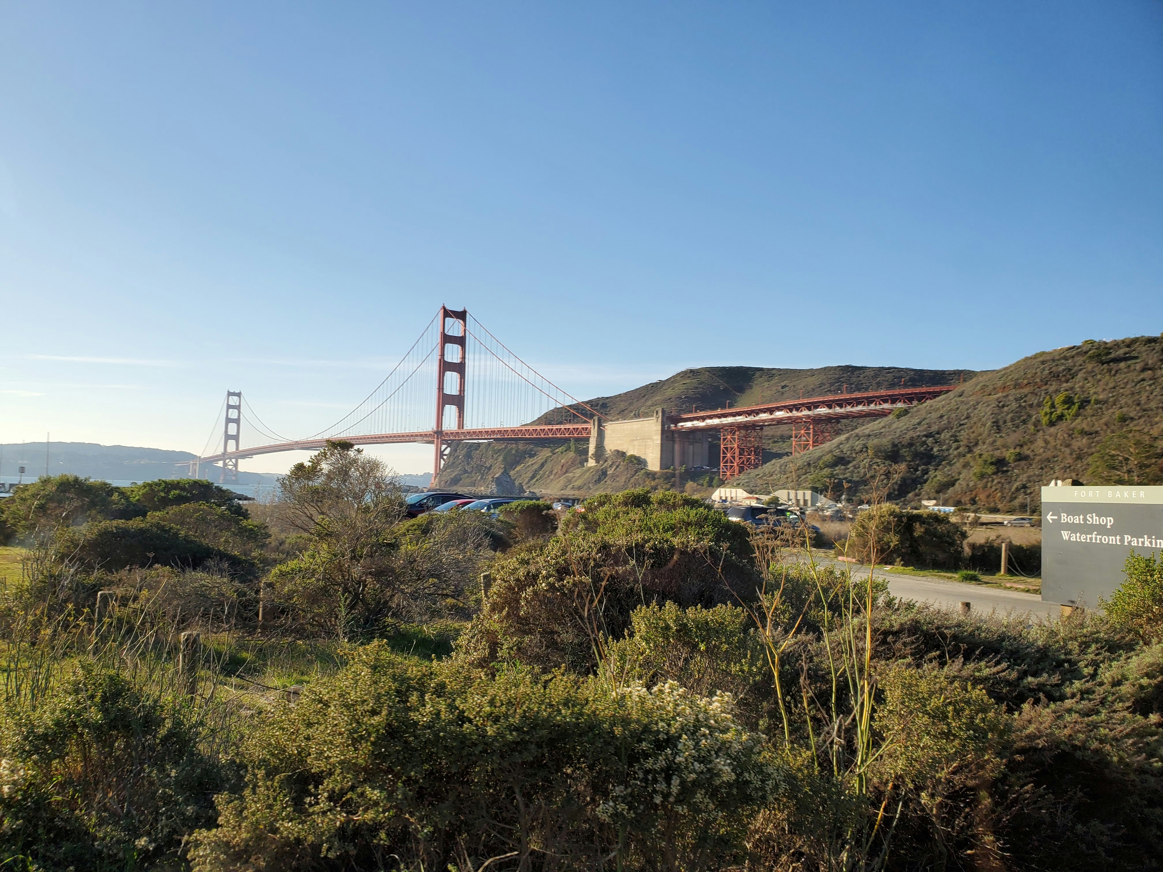 Golden Gate Bridge spans Marin Hills under a bright, clear blue sky.
