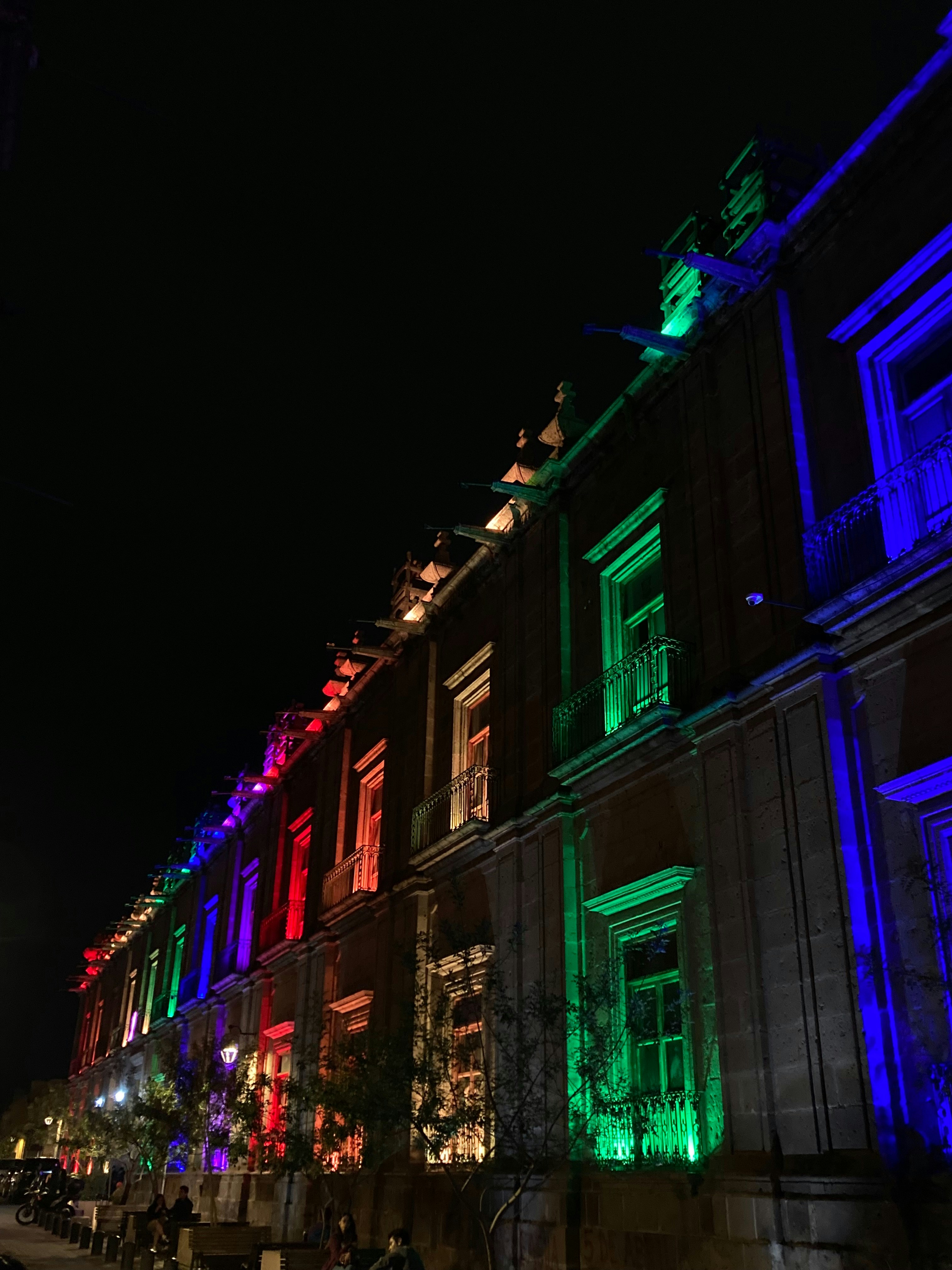 Prismatic Facade: Night Rainbow Drapes a Historic Block
