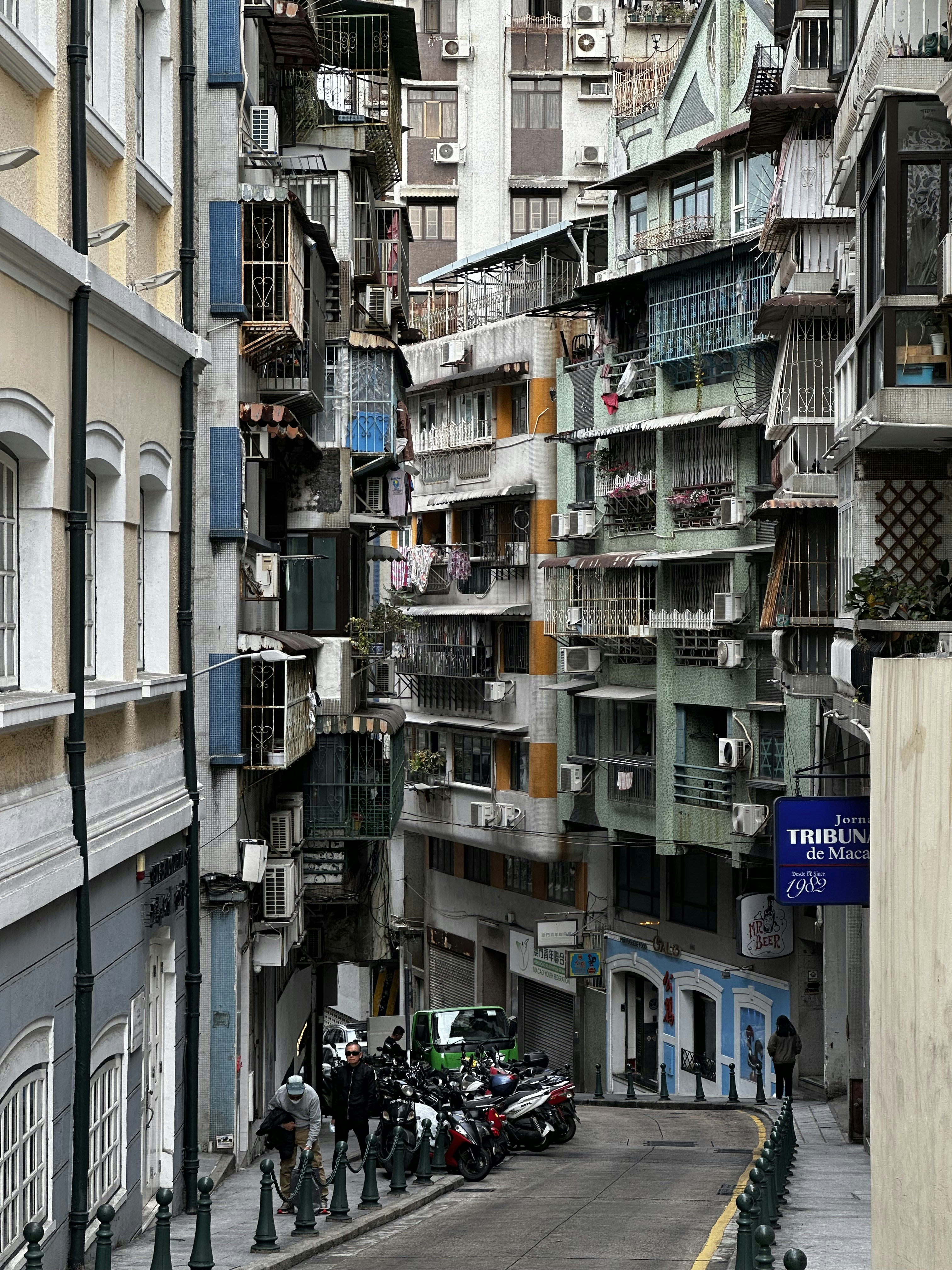 Cascading Facades: A Narrow Street Framed by Balconies and Scooters