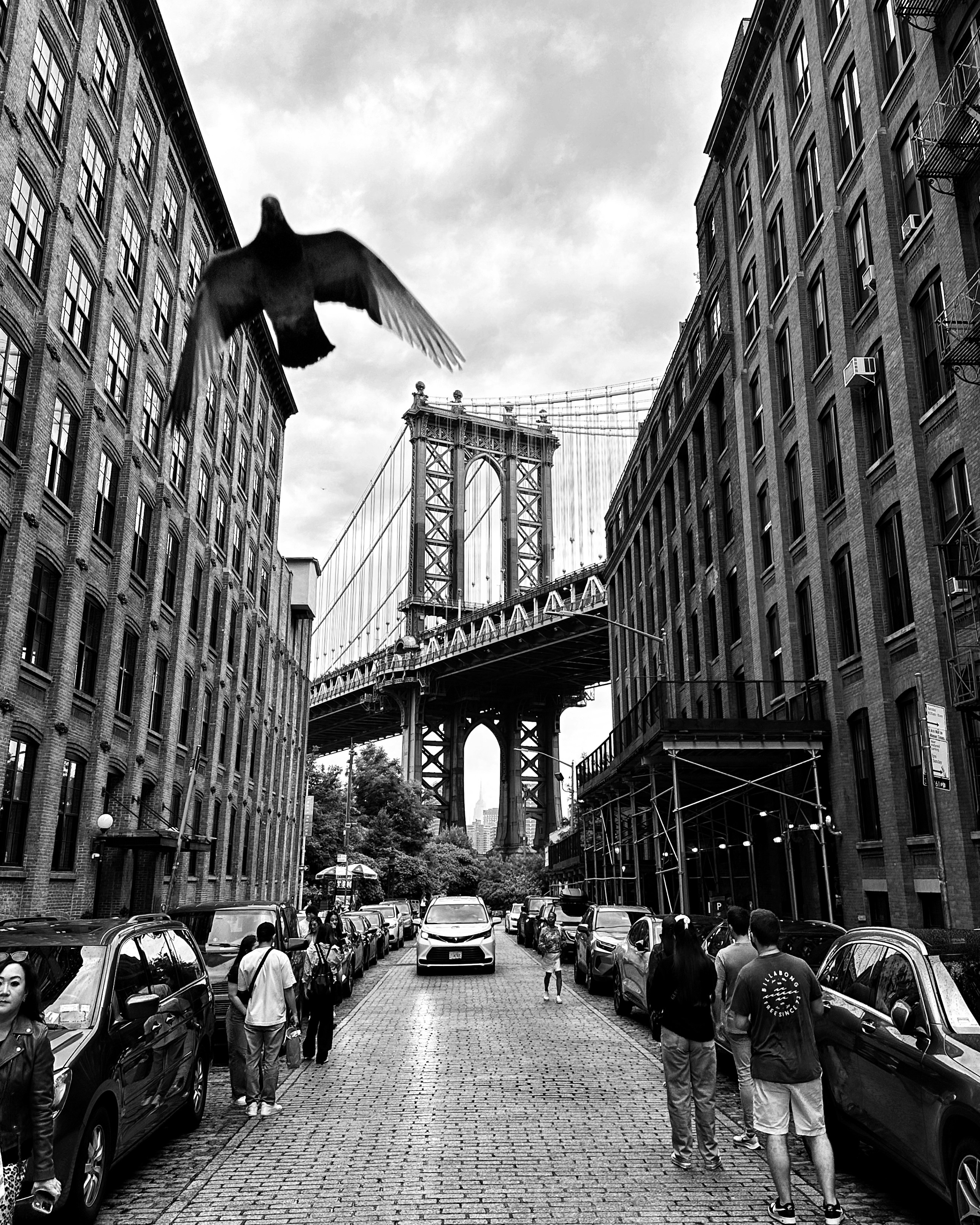 Grayscale Crossing: Narrow Street Framing a Steel Bridge