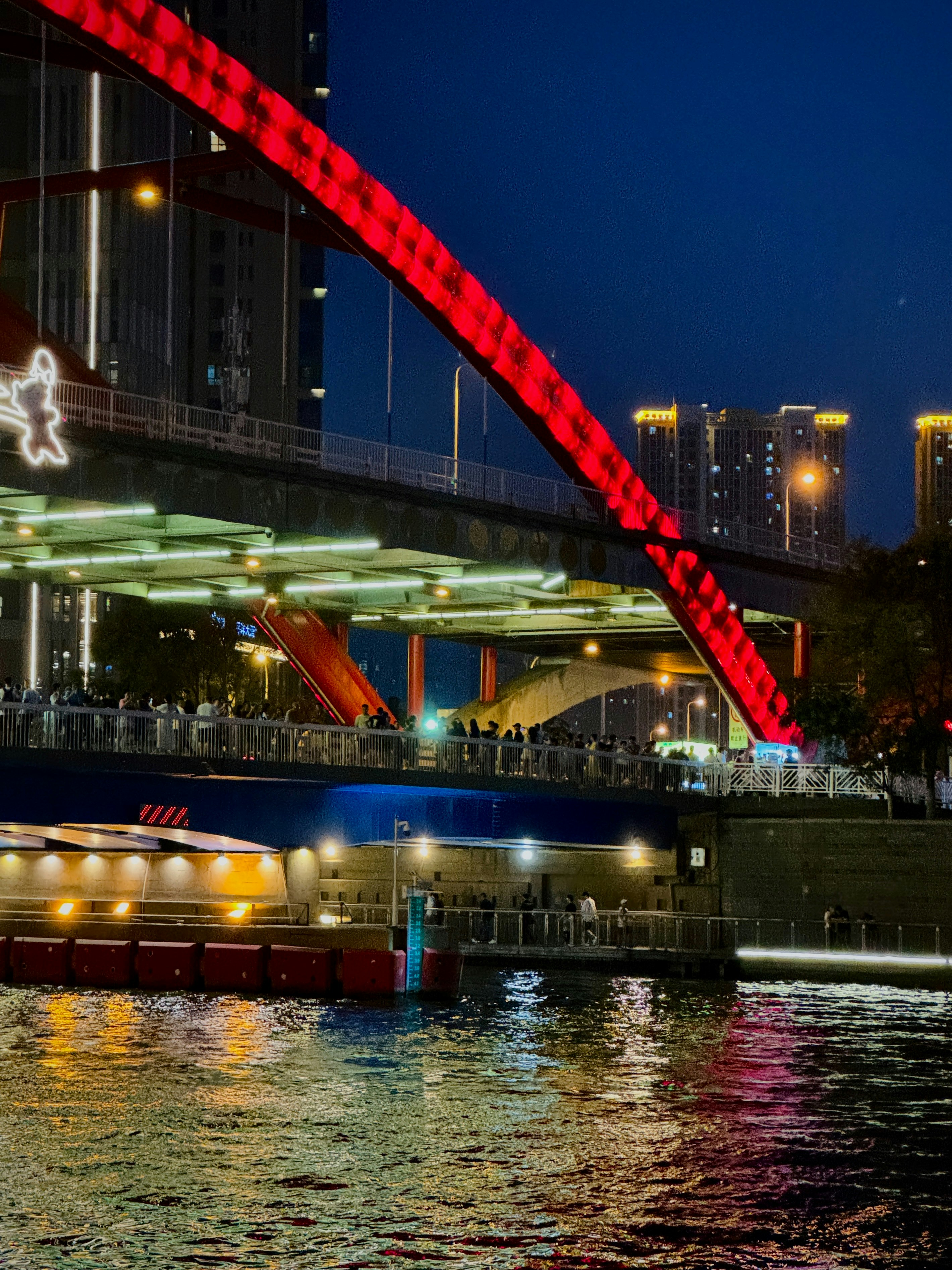A large red bridge over a river next to a tall building photo – Free ...