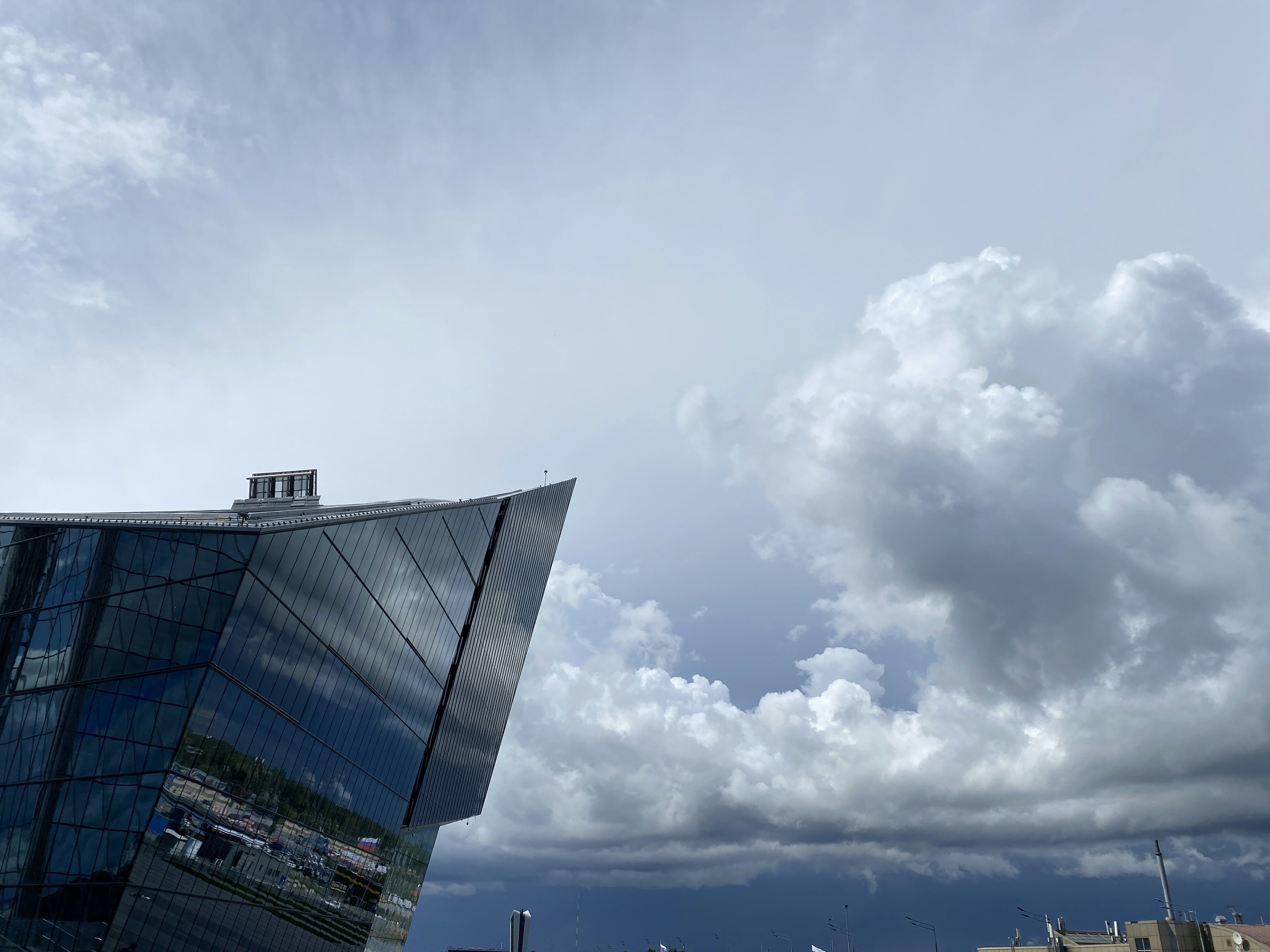 Edge of Glass: A Slanted Facade Reaching Into a Clouded Sky