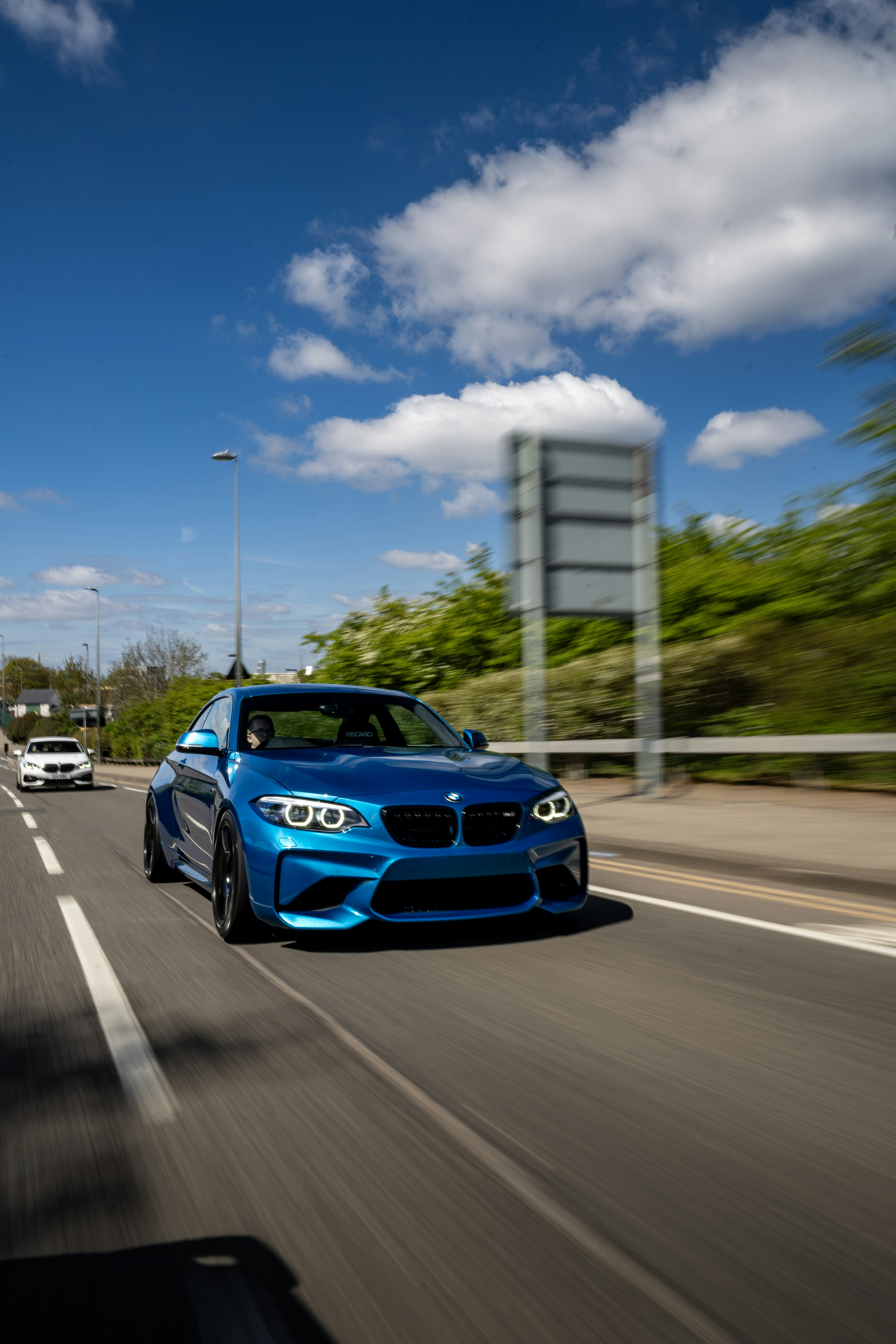 A blue car driving down a highway next to a forest photo – Free Bmw ...