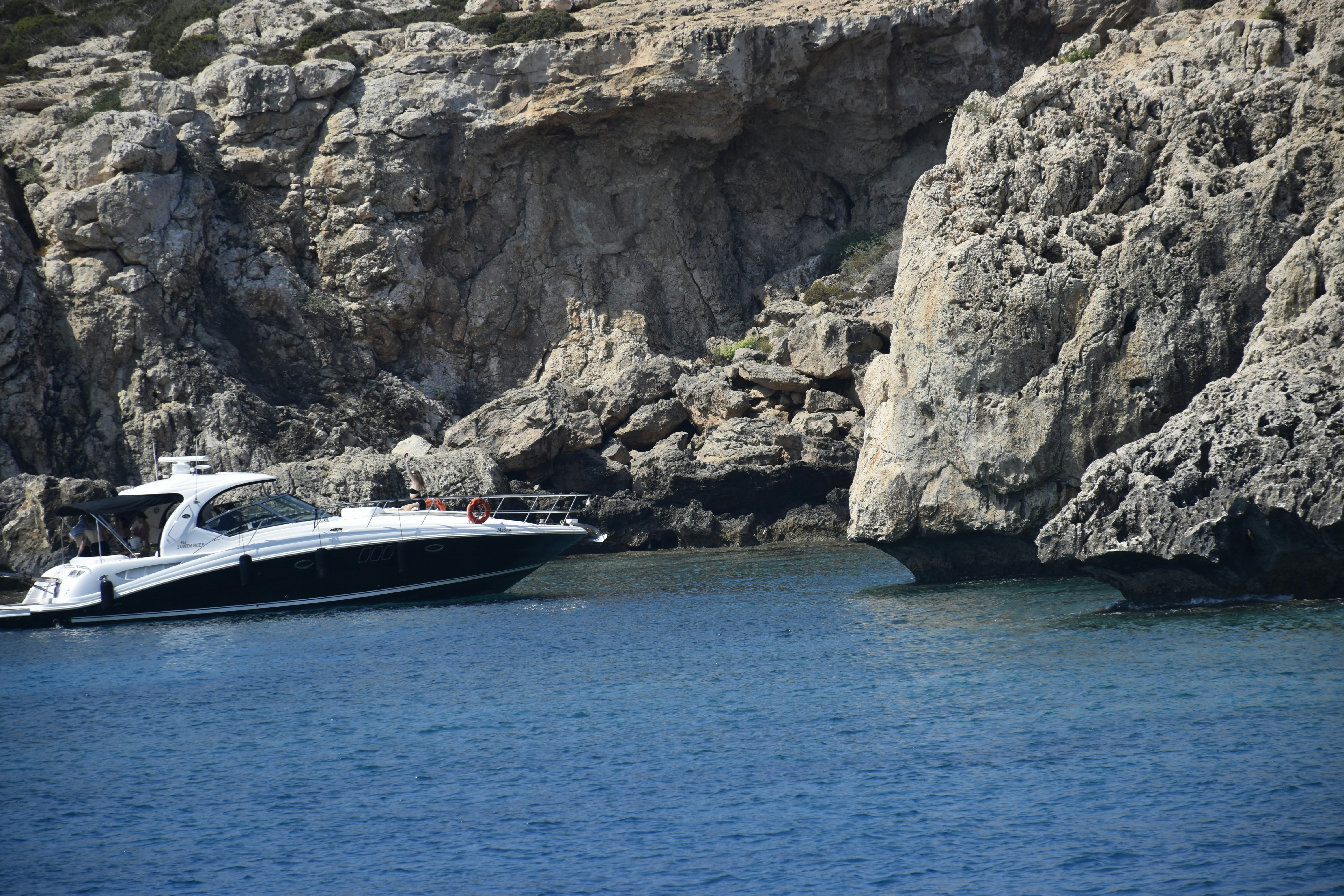 A boat in a body of water near a rocky cliff photo – Free Vehicle Image ...