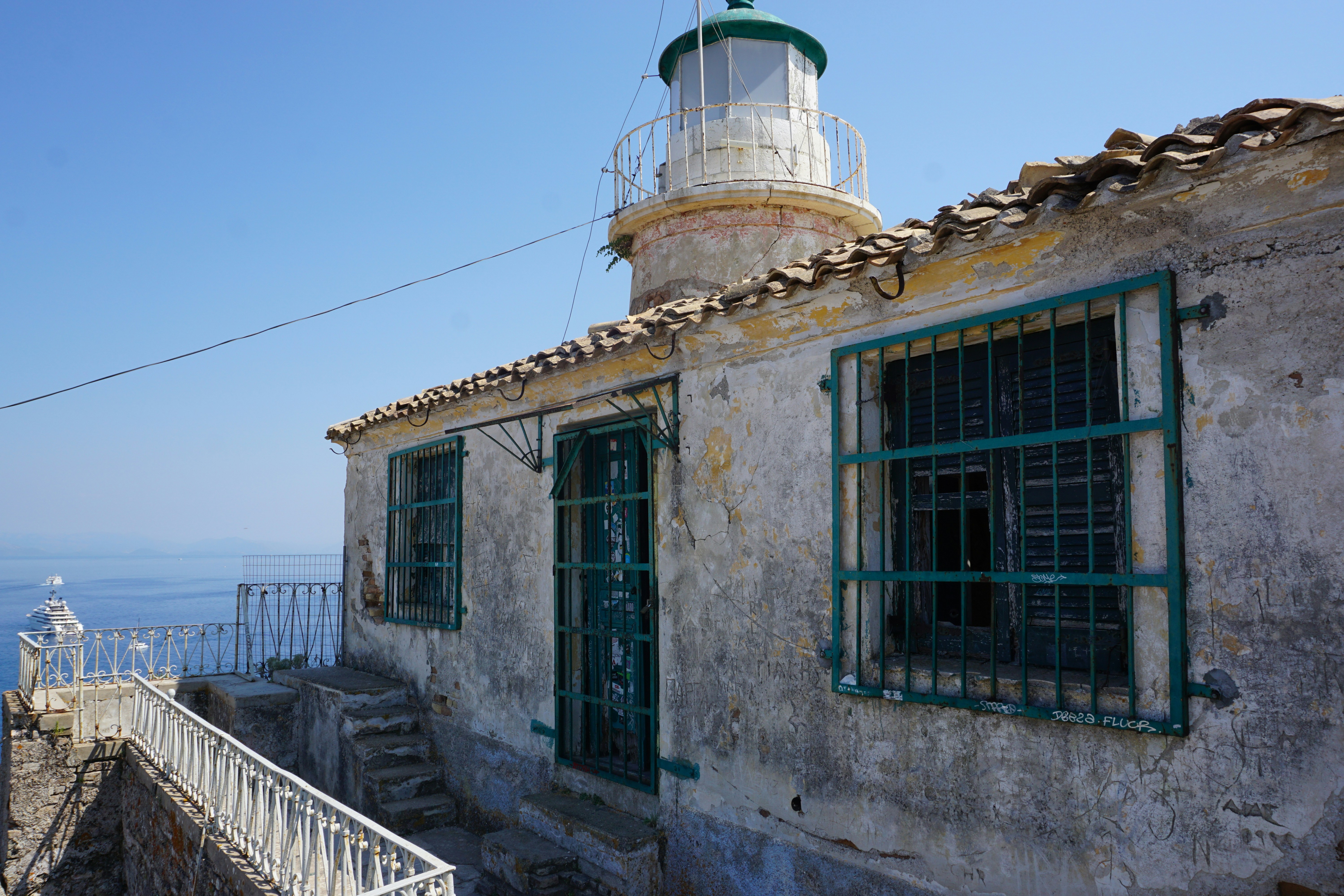 Azure Grilles and a Cliffside Lighthouse: Weathered Charm by the Sea