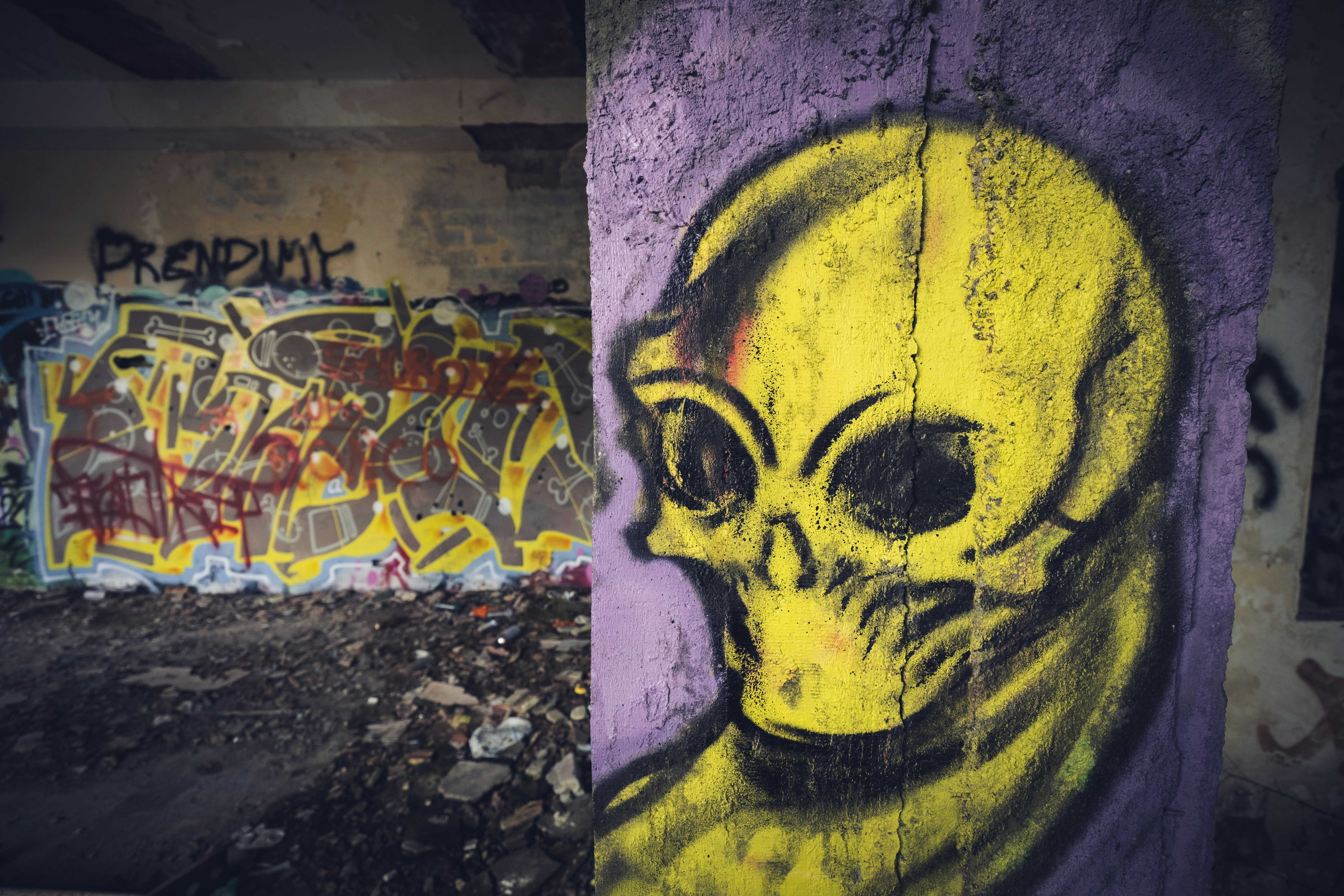 A graffiti covered wall with a yellow alien head on it photo – Free Art ...