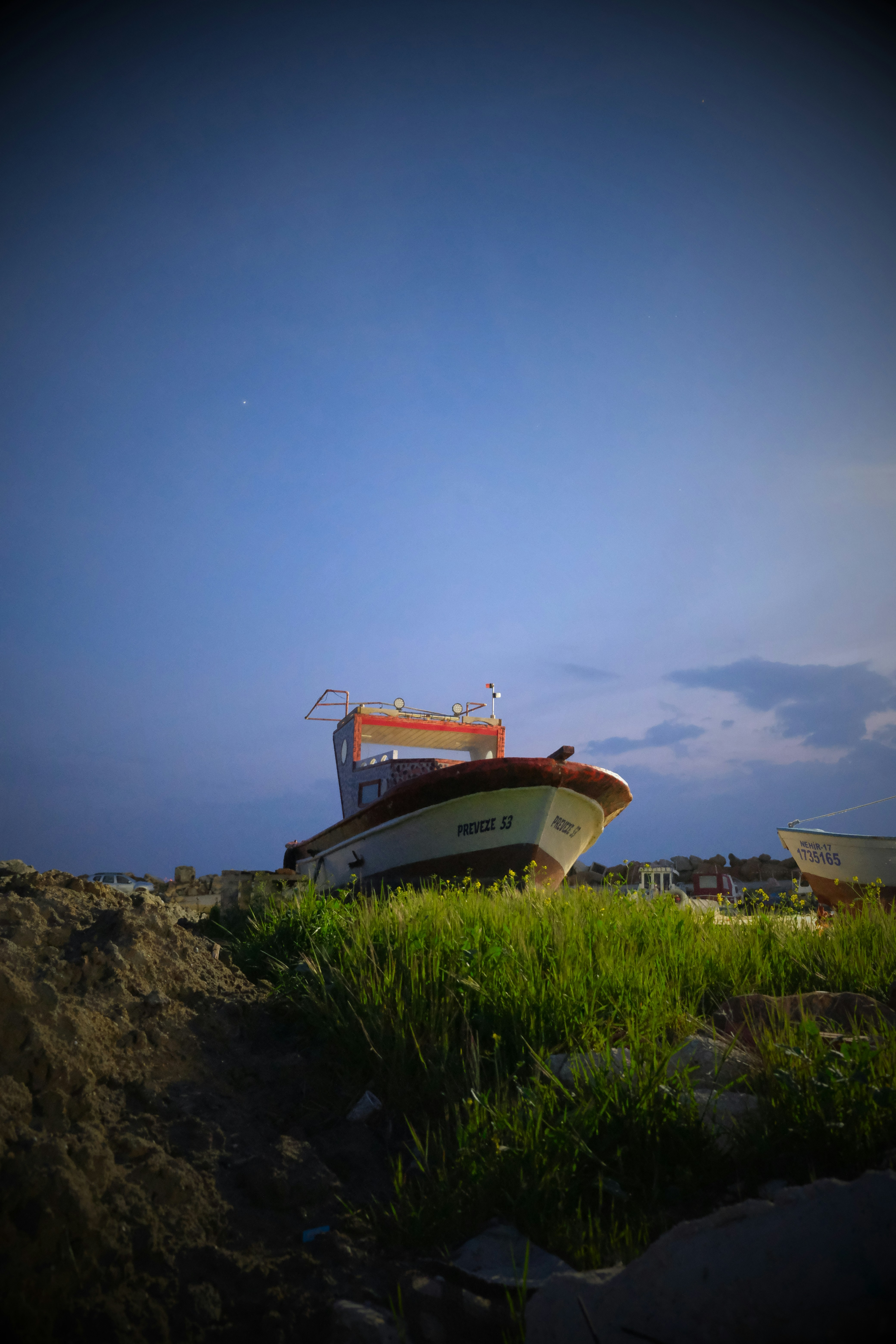 Blue Hour Drift: a weathered harbor boat resting among grasses