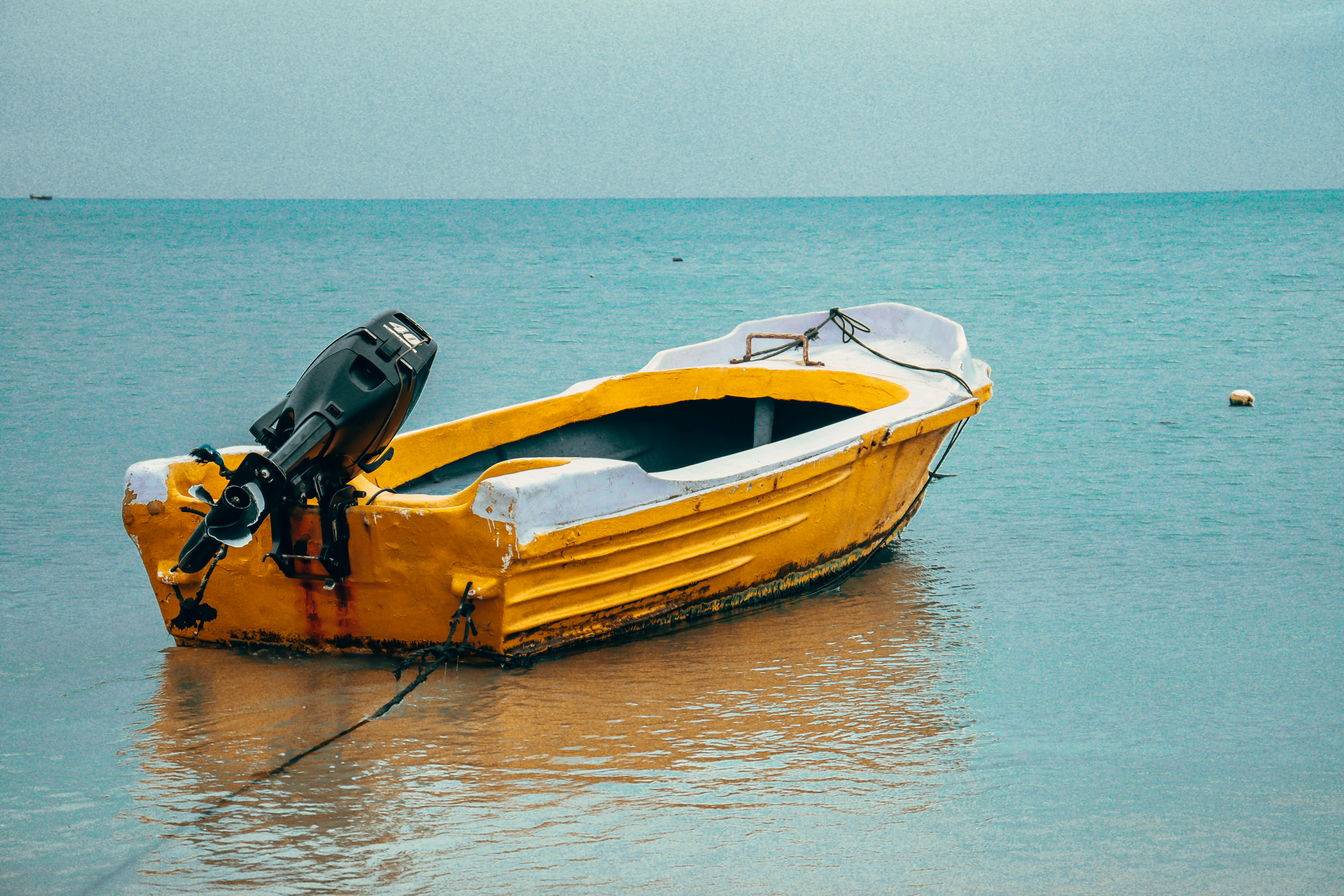 A yellow boat sitting in the middle of the ocean photo – Free Dinghy ...