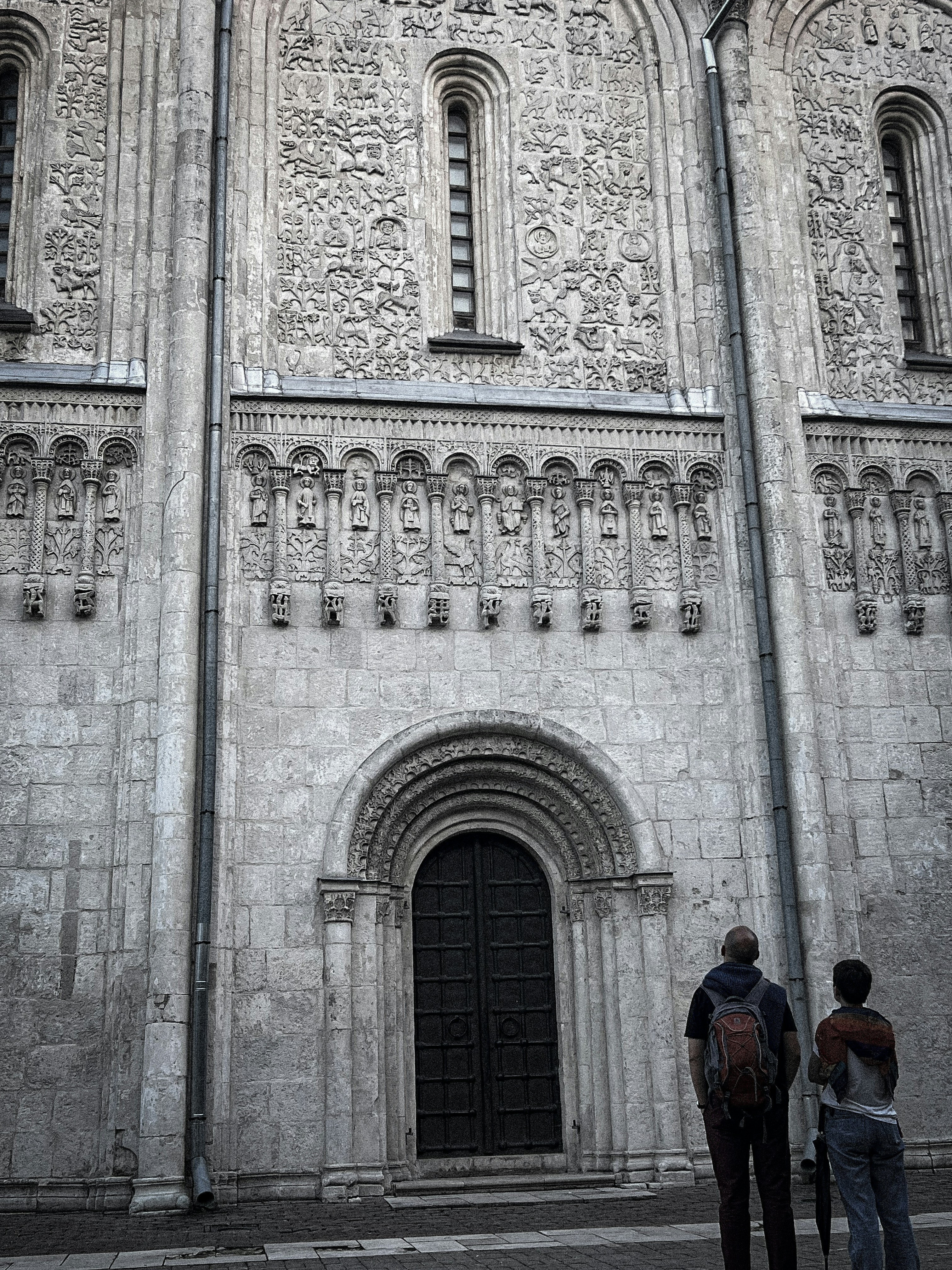 Stone Choir Portal: Carved Facade Framed by Two Wanderers