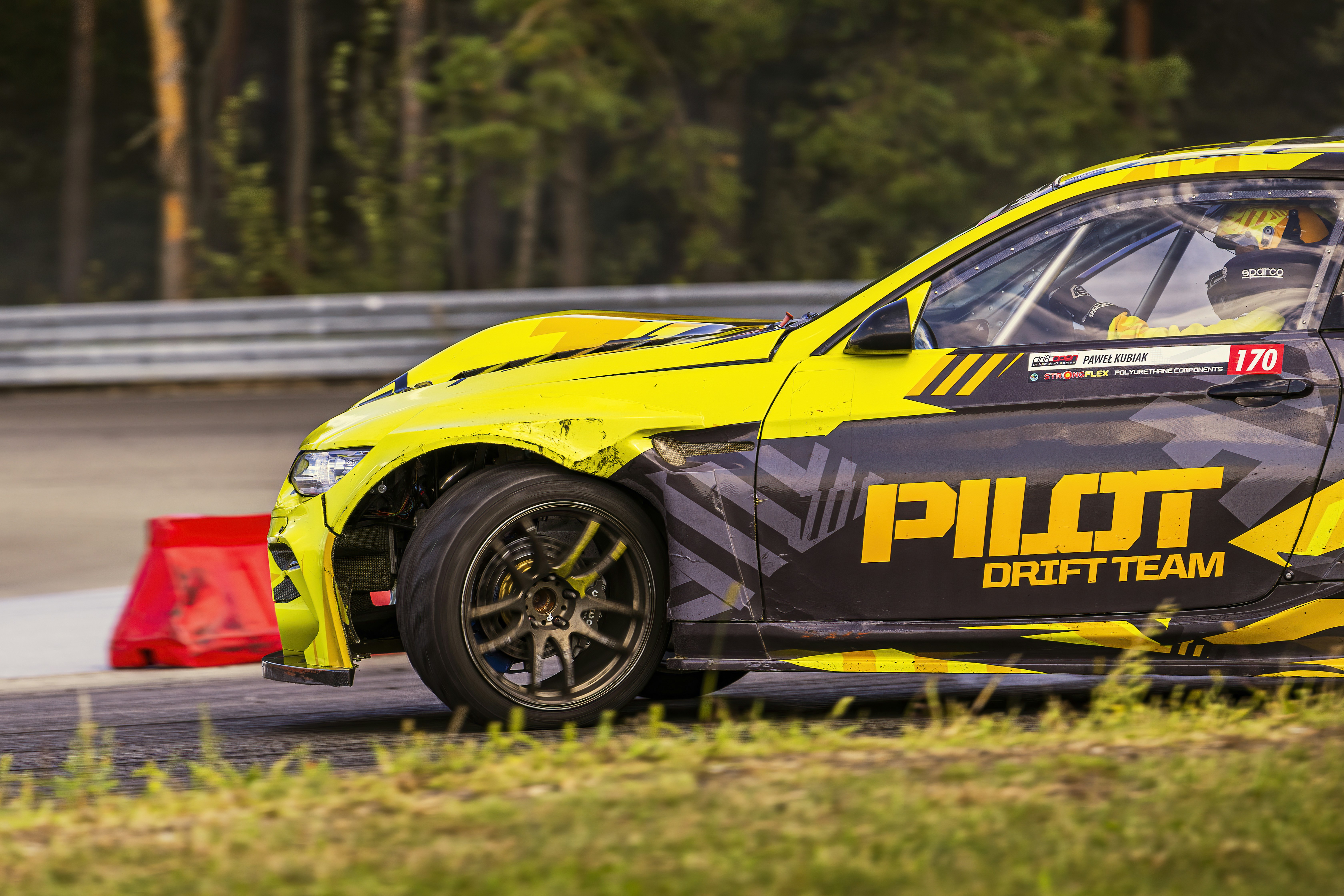 A yellow and black car driving on a race track photo – Free Machine ...