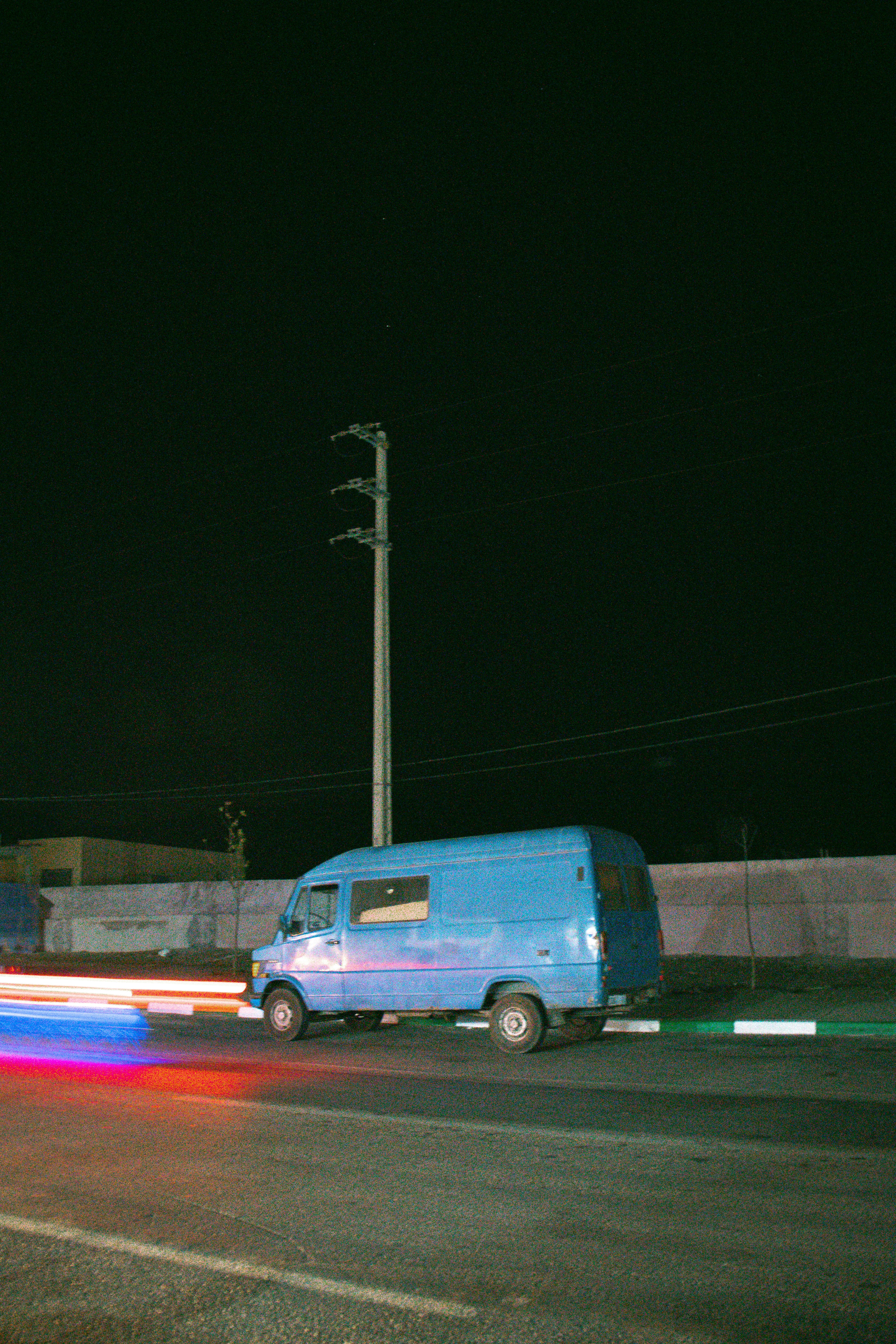 Midnight Blue Van on a Quiet Road as Neon Tail Lights Blur