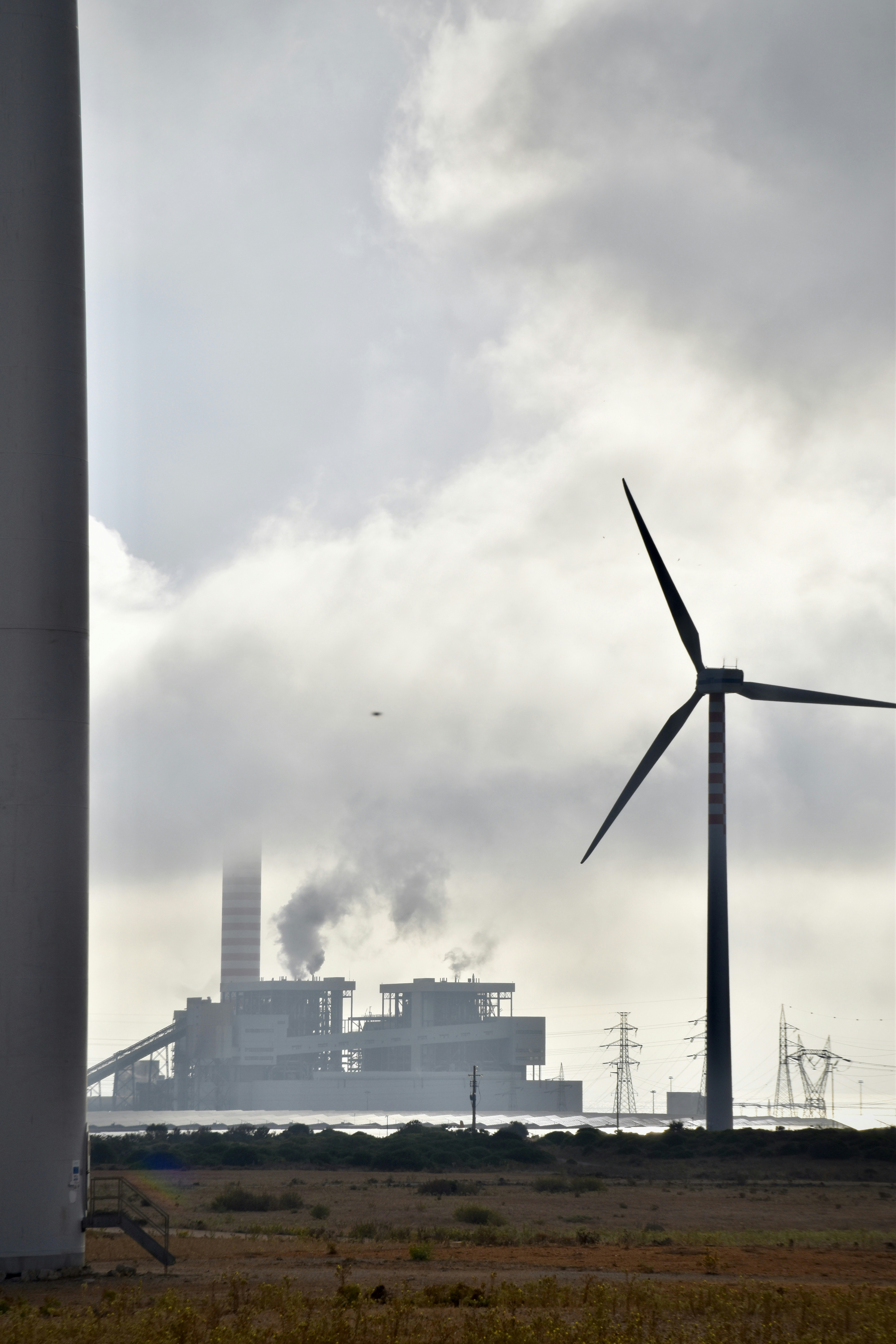 A wind turbine and a factory in the background photo – Free Italy Image ...