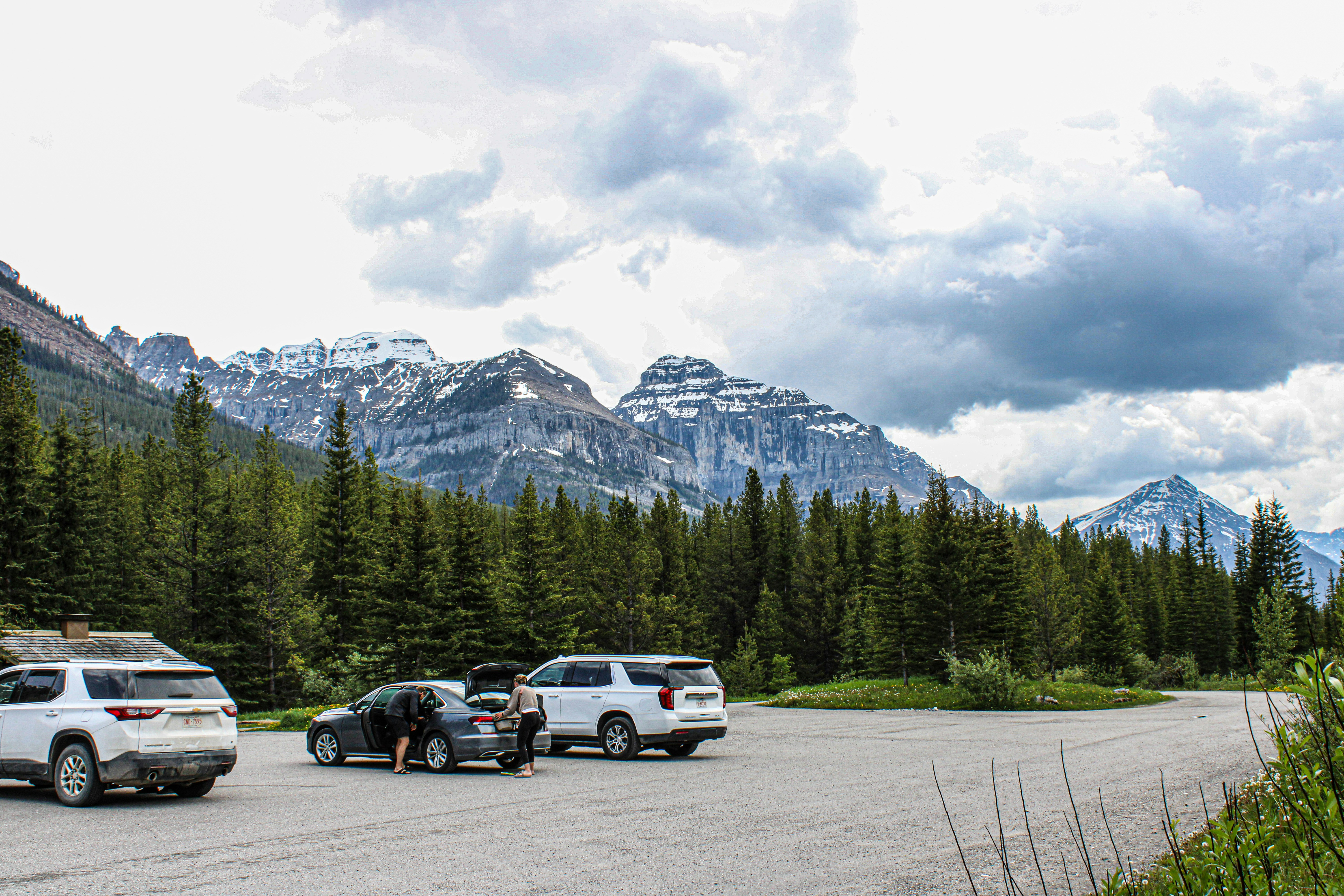 A group of cars parked in a parking lot with mountains in the ...