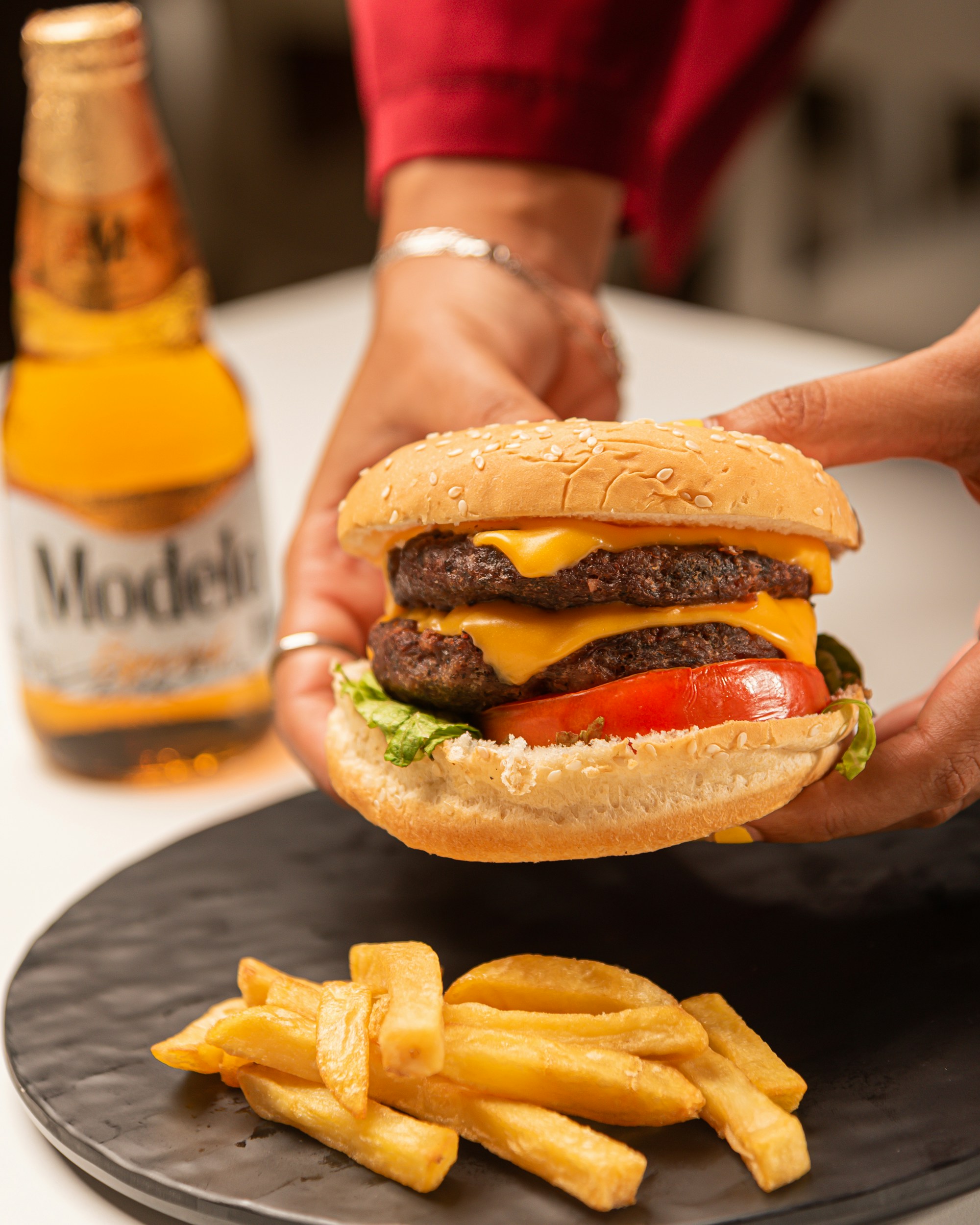 Double-Stack Cheeseburger Close-Up with Fries and a Modelo in the Background