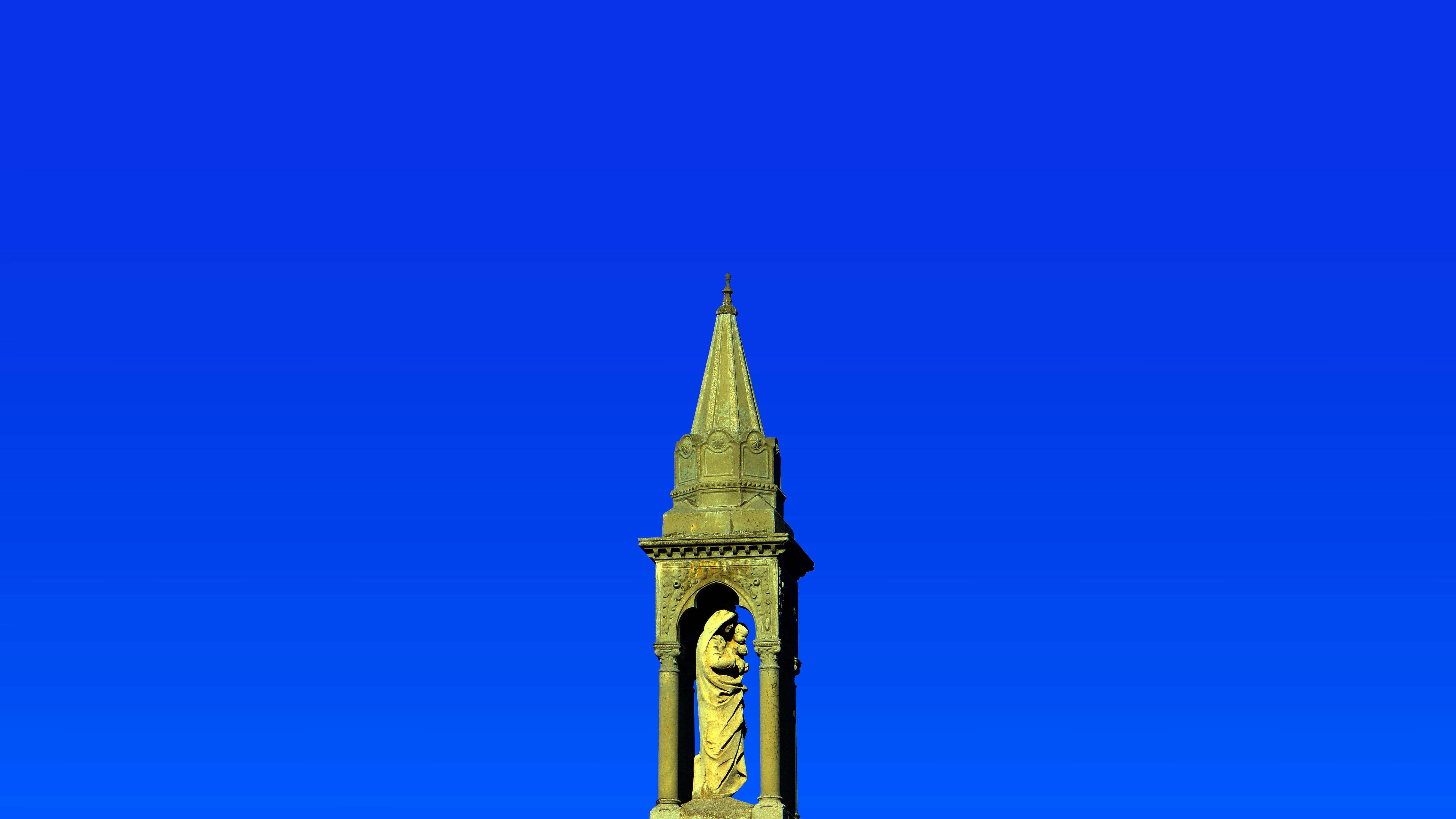 Gilded Sentinel under a slender spire against a cobalt sky