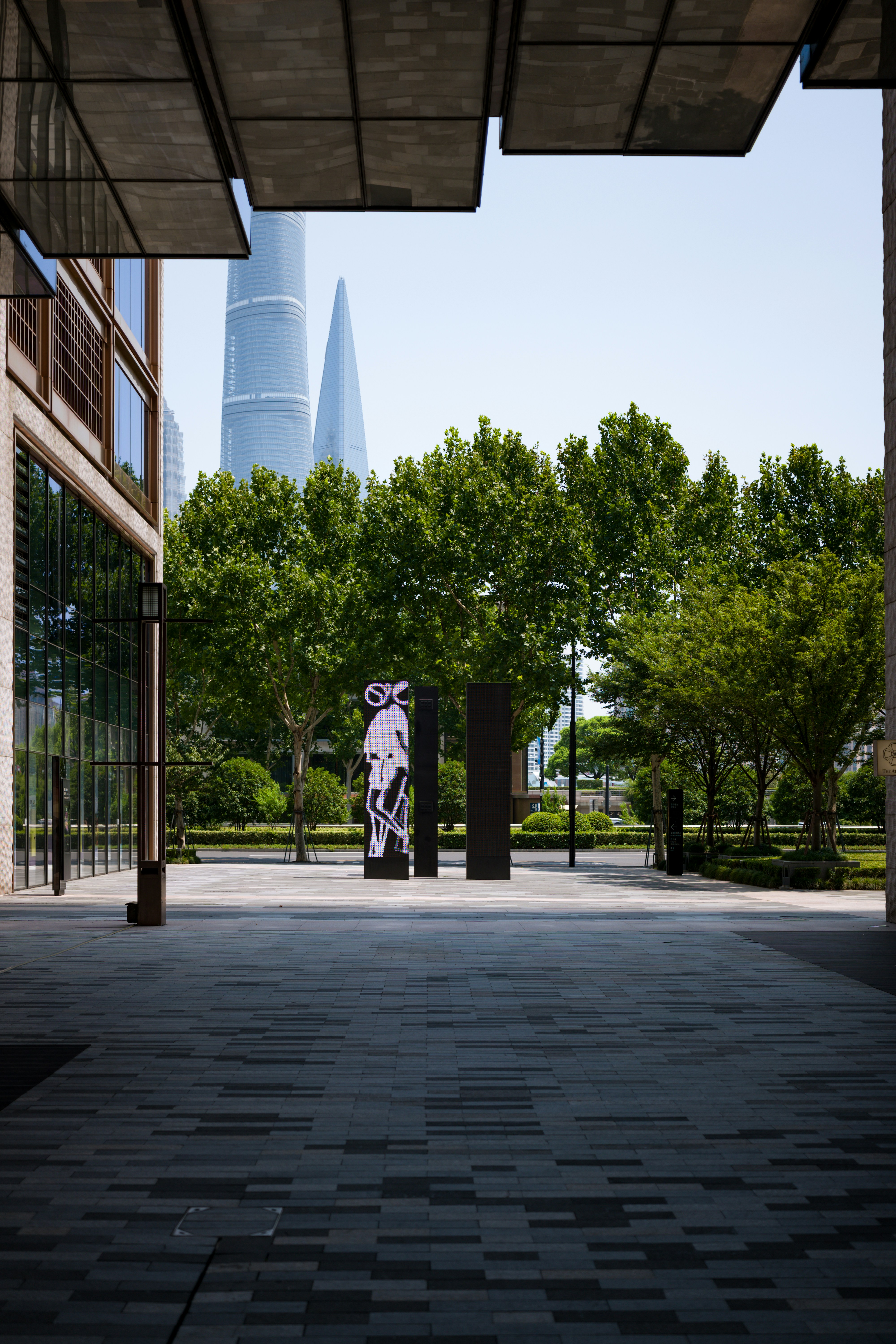 Centerline Sculpture under an Urban Canopy: Glass, Trees, and Towers