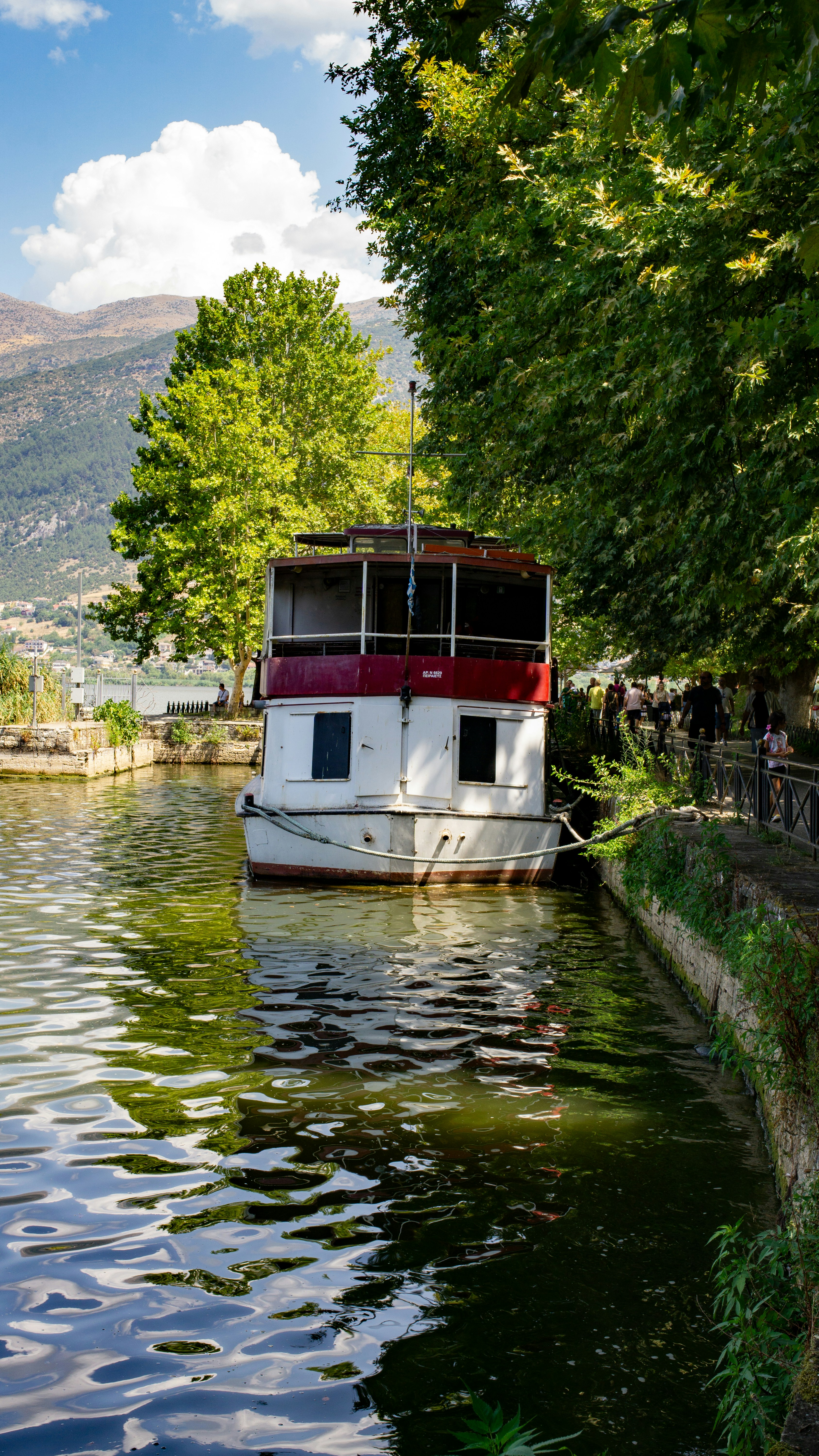 A boat floating down a river next to a lush green hillside photo – Free ...