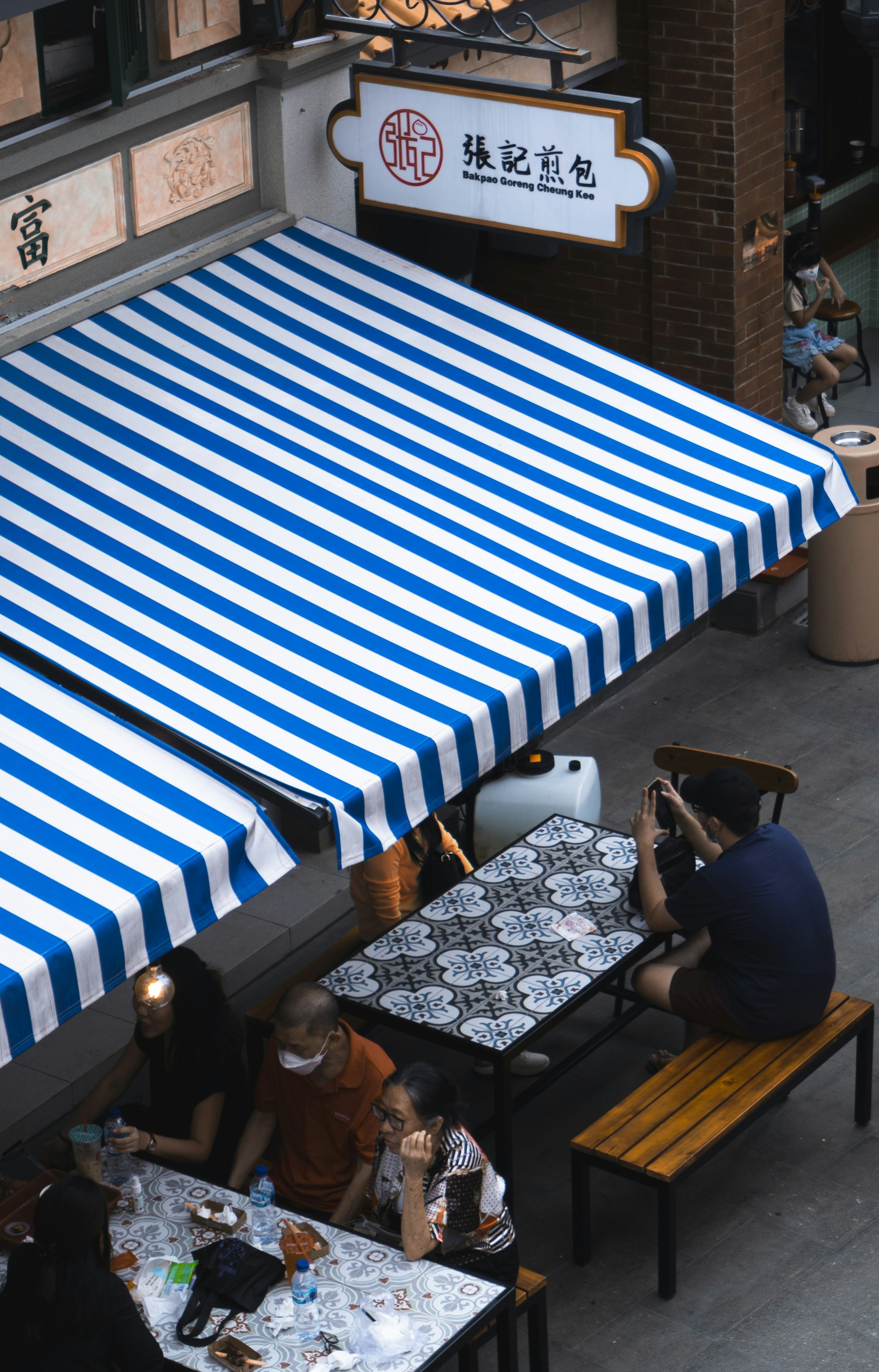 Stripe-Lined Terrace: A Street Café Scene Under Blue Awnings