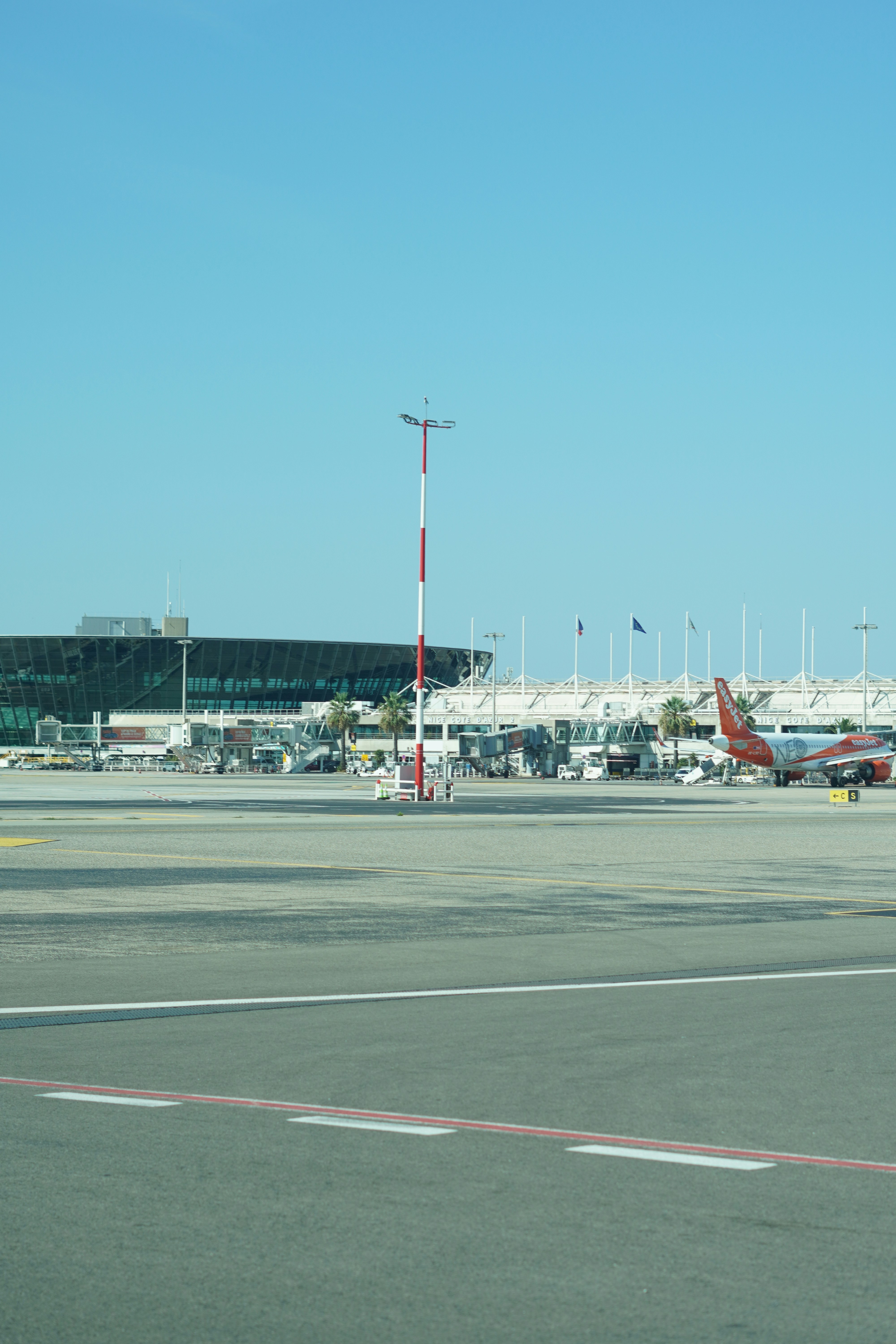 Expansive airport tarmac with aircraft parked under a clear blue sky.