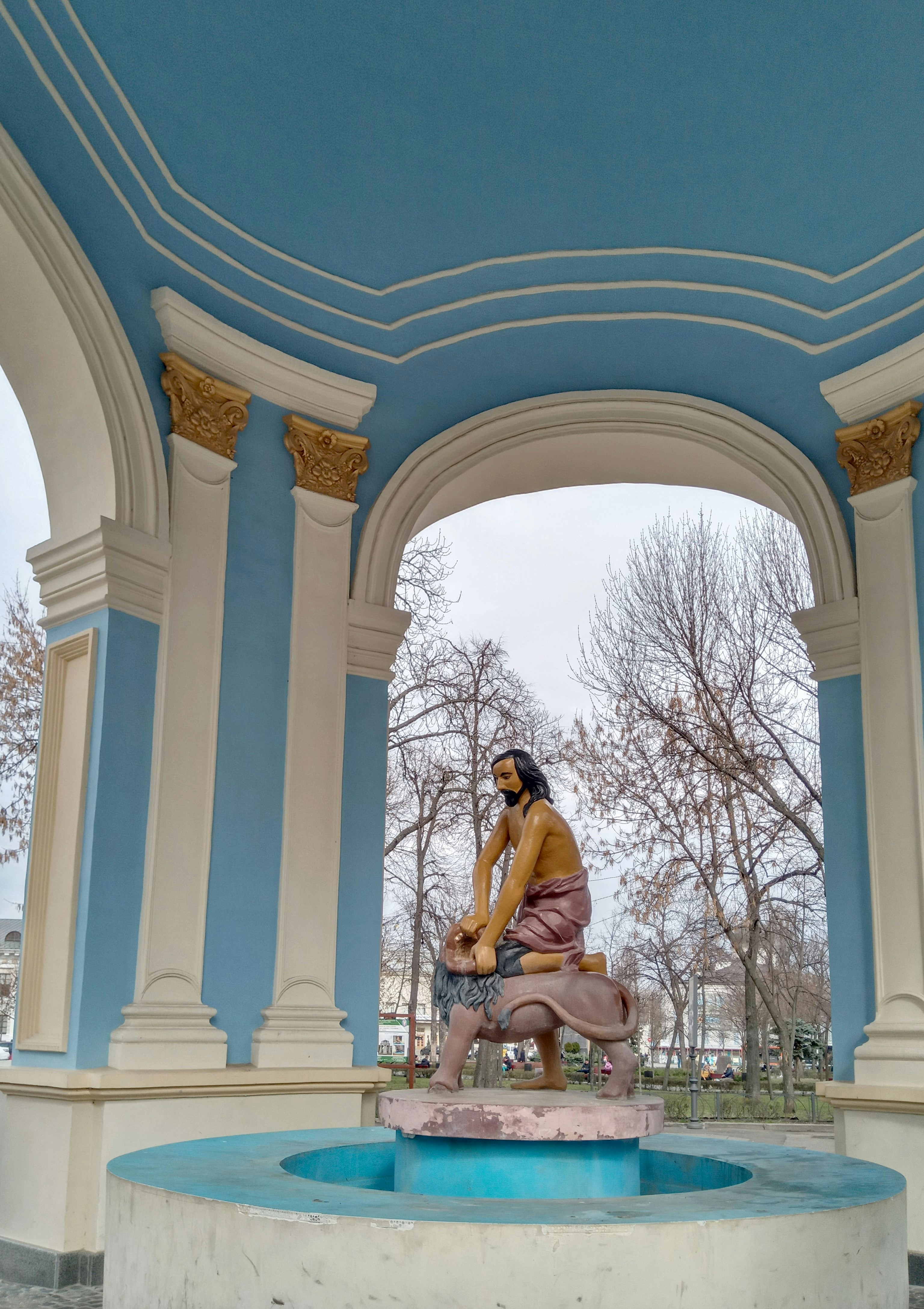 Azure Arches, Bronze Stillness: A Kneeling Statue in Winter Light