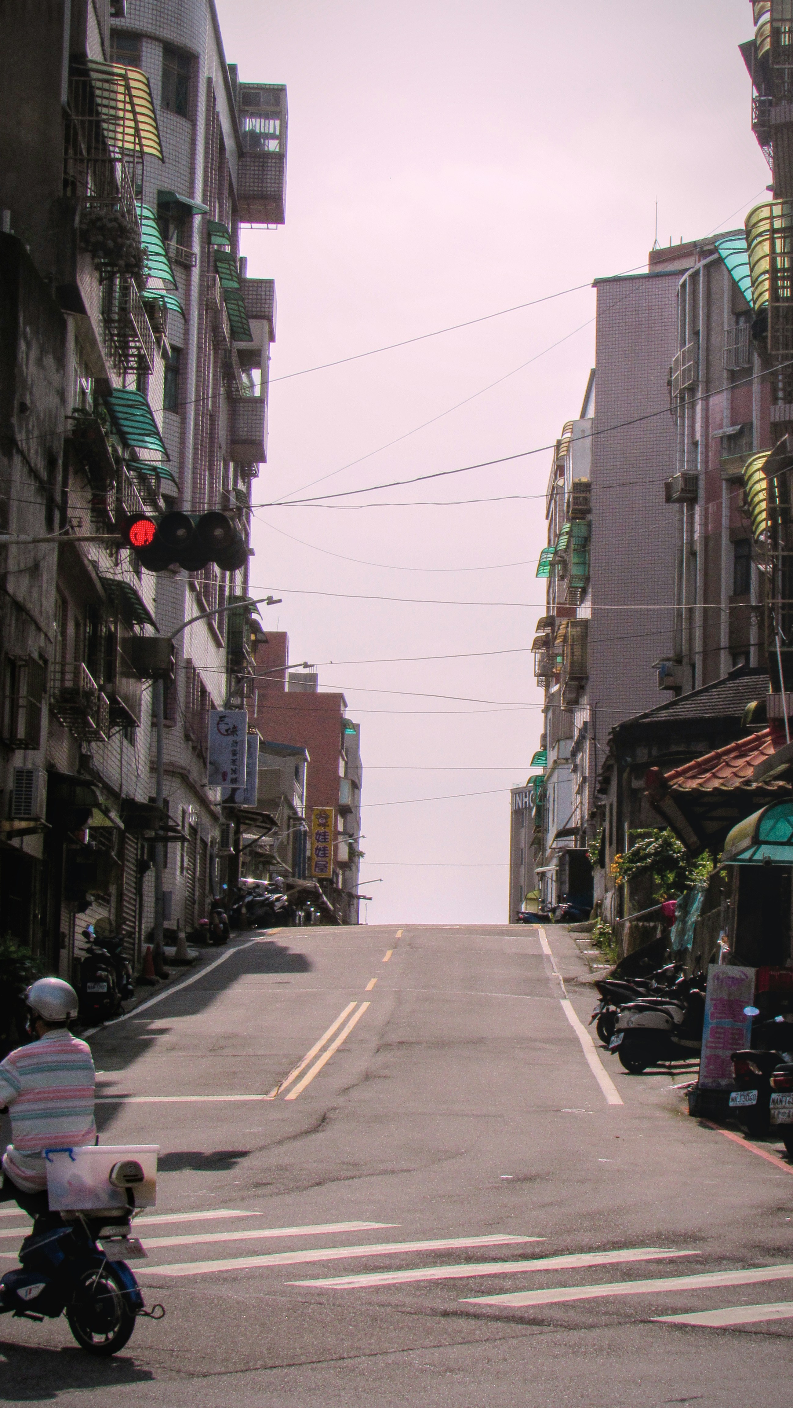 Vanishing Uphill Street Between Wires and Neon Balconies