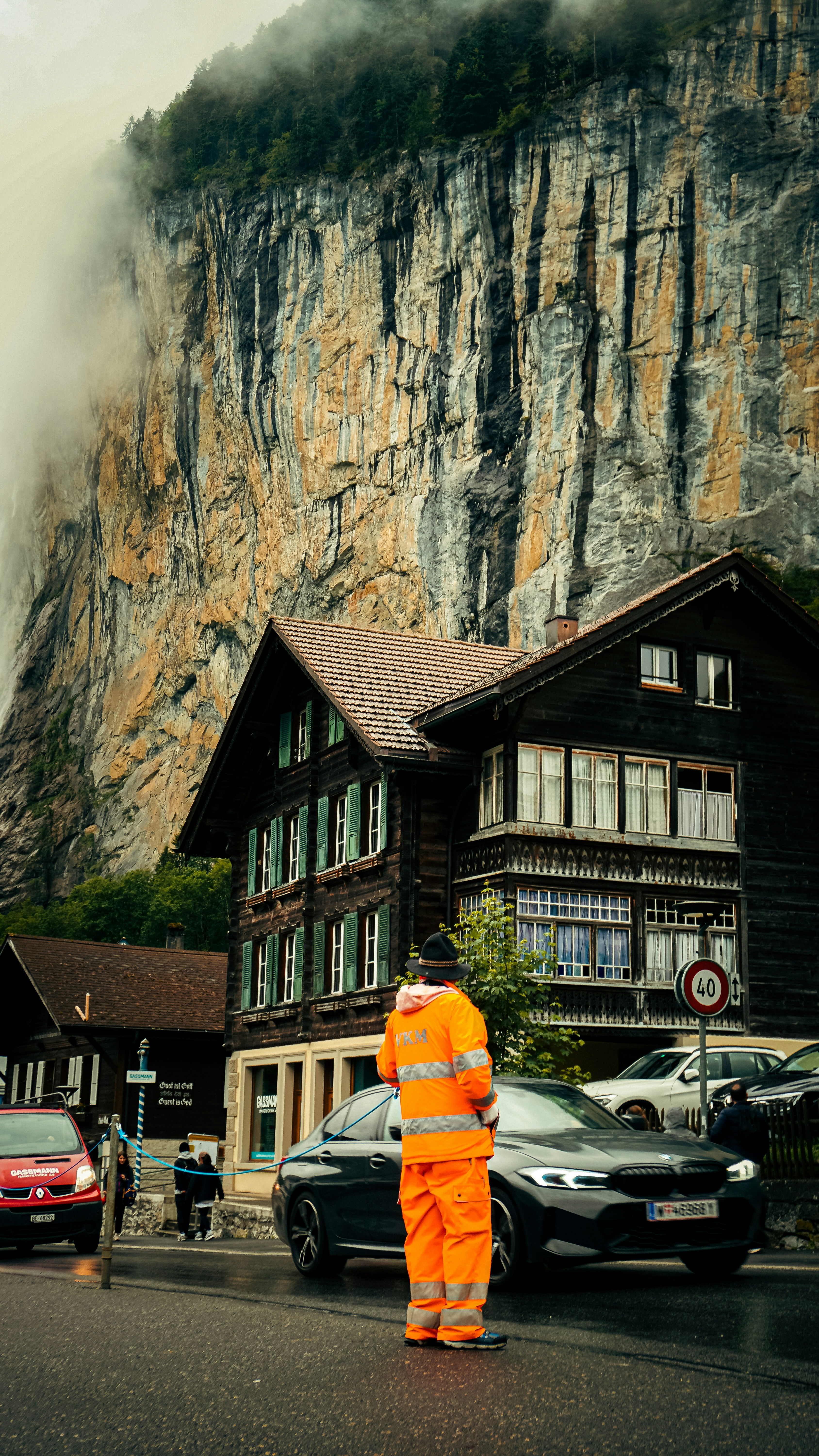 High-Altitude Roadblock: Orange Suit in a Village Beside a Cliff