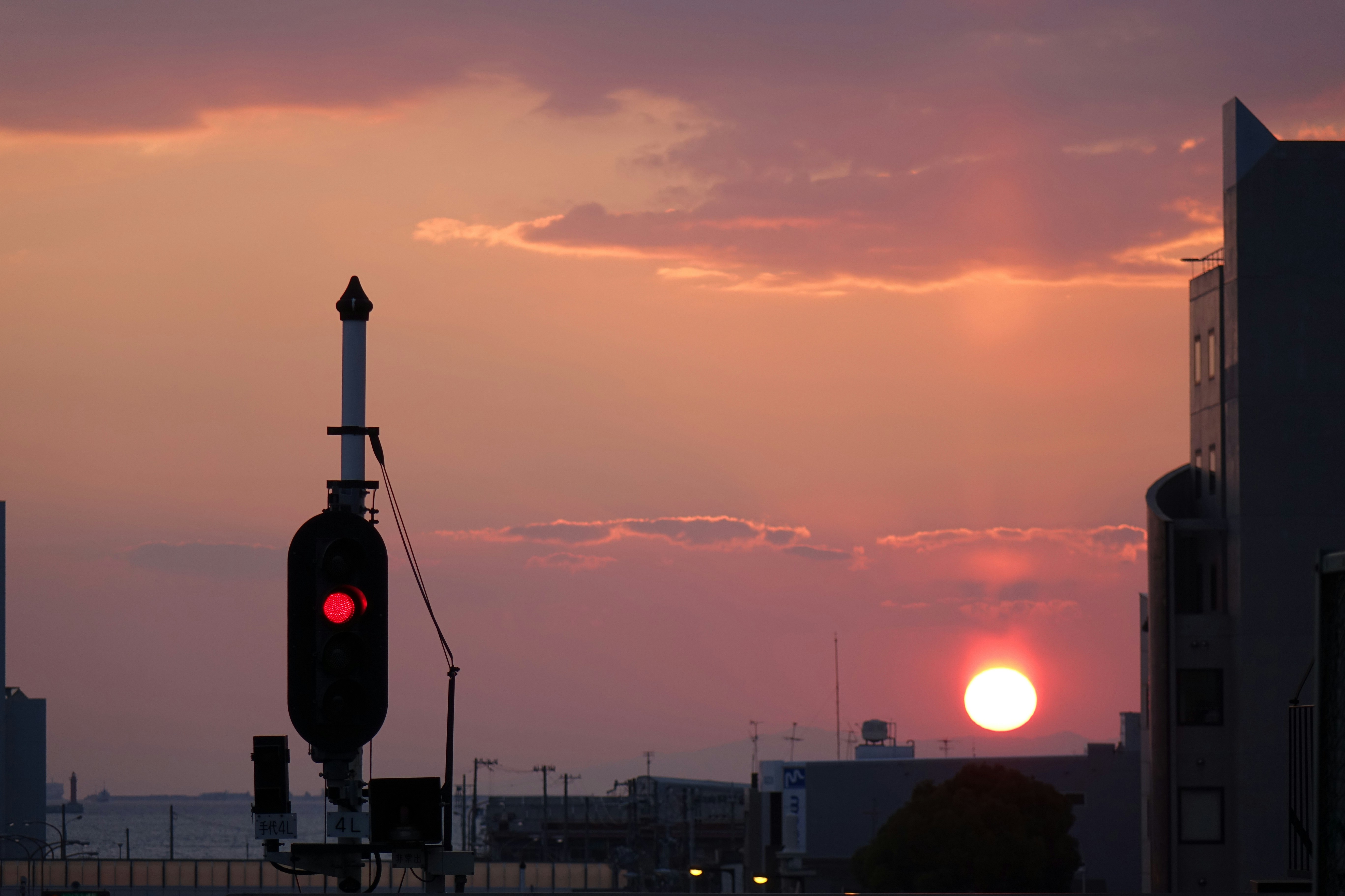 Crimson Stoplight at Dusk Over a Quiet Riverside Cityscape