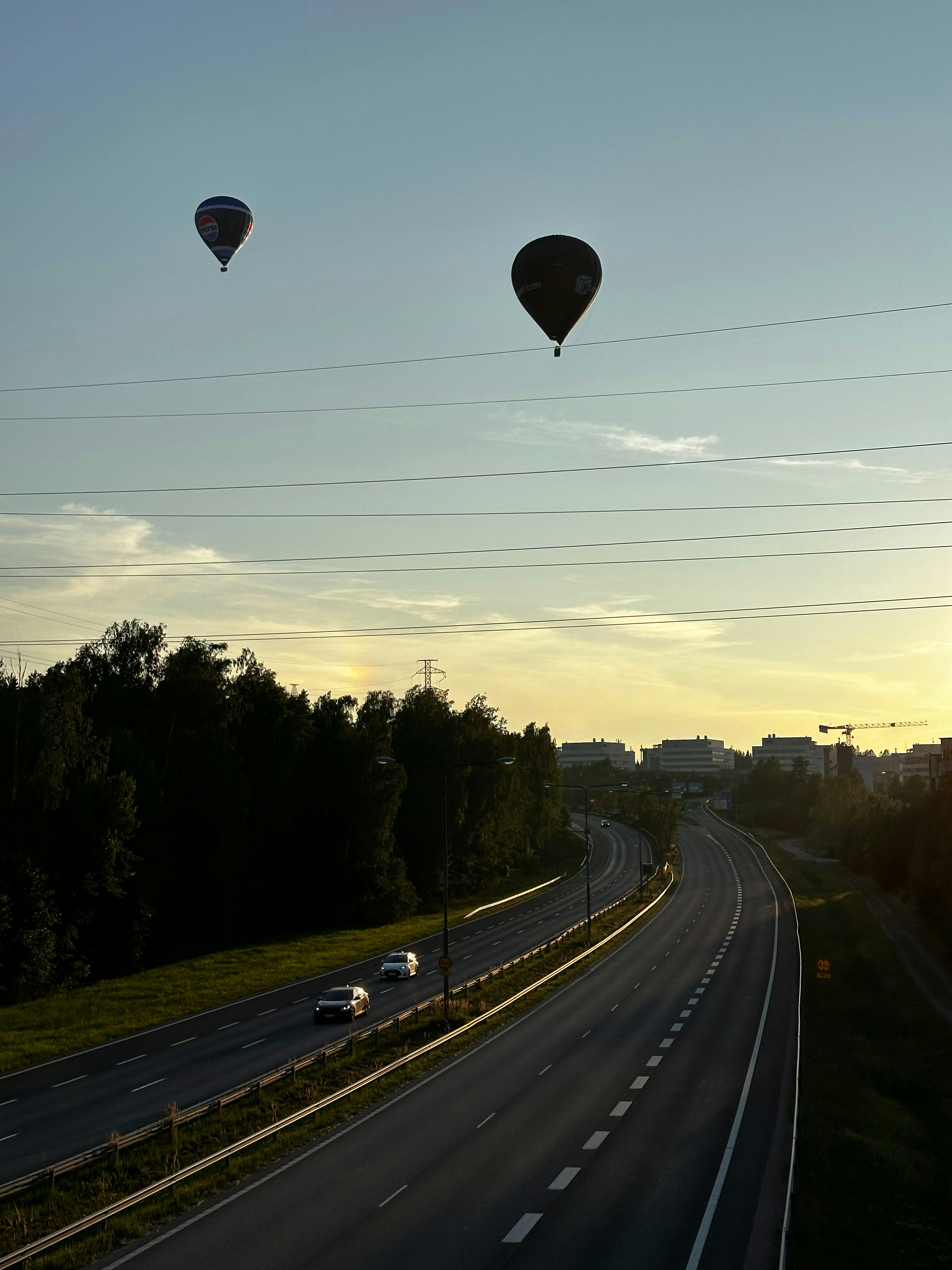 Mid-Sunset Lift: Two Balloons Hover Over the Quiet Expressway