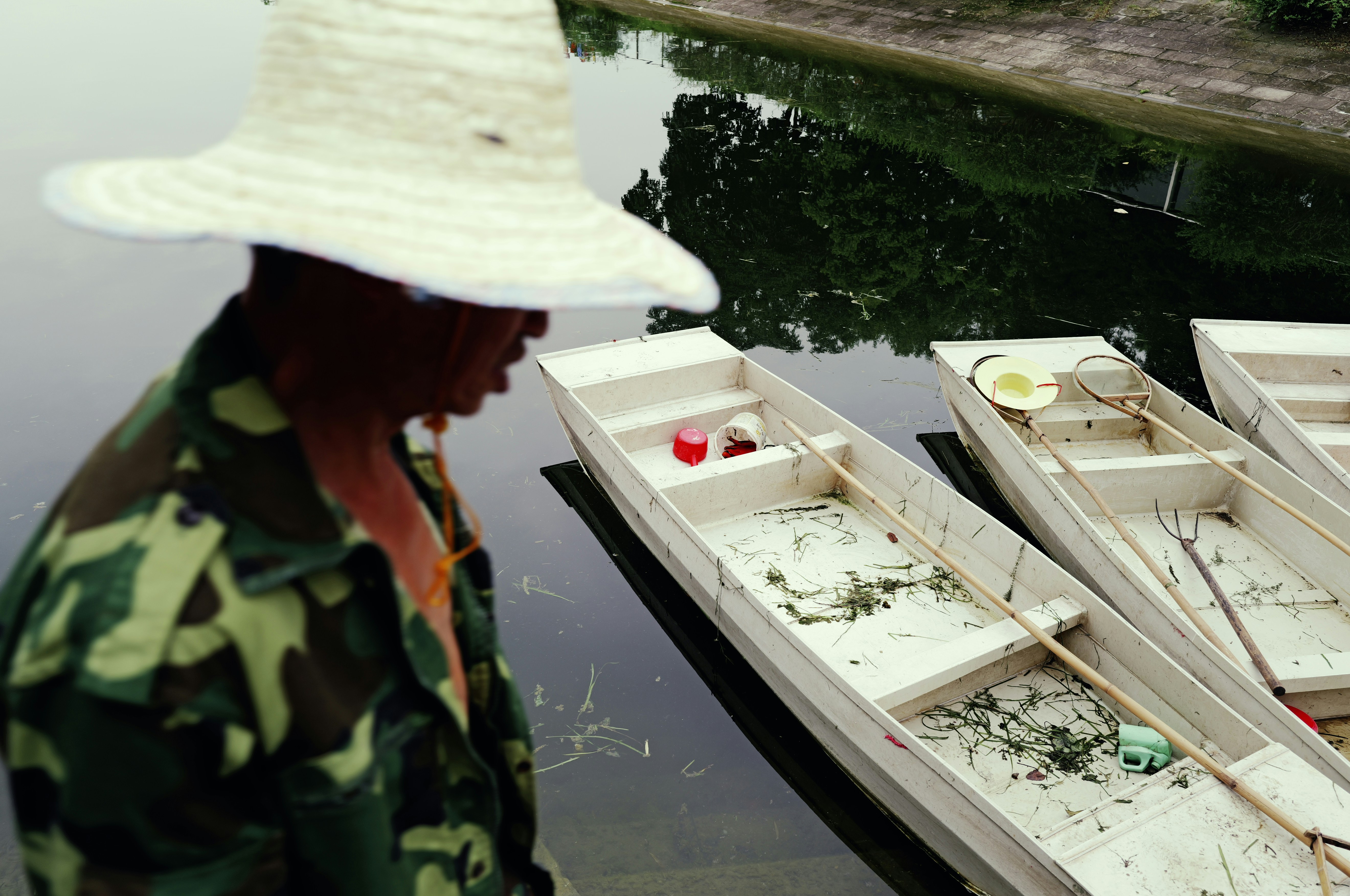 A woman in a hat standing next to a row boat