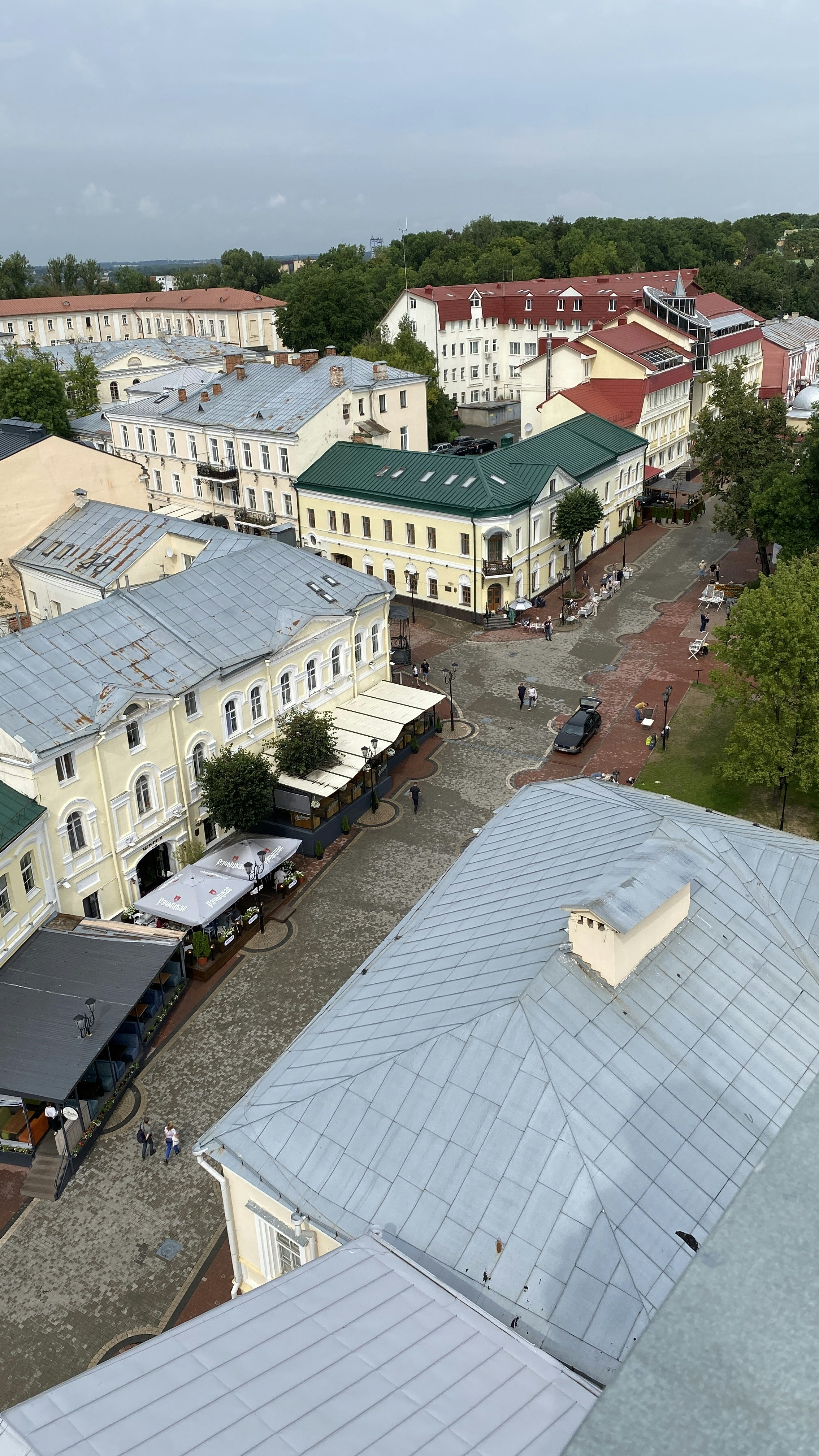 Aerial view of a charming urban landscape featuring historic buildings and bustling streets lined with trees and outdoor seating.