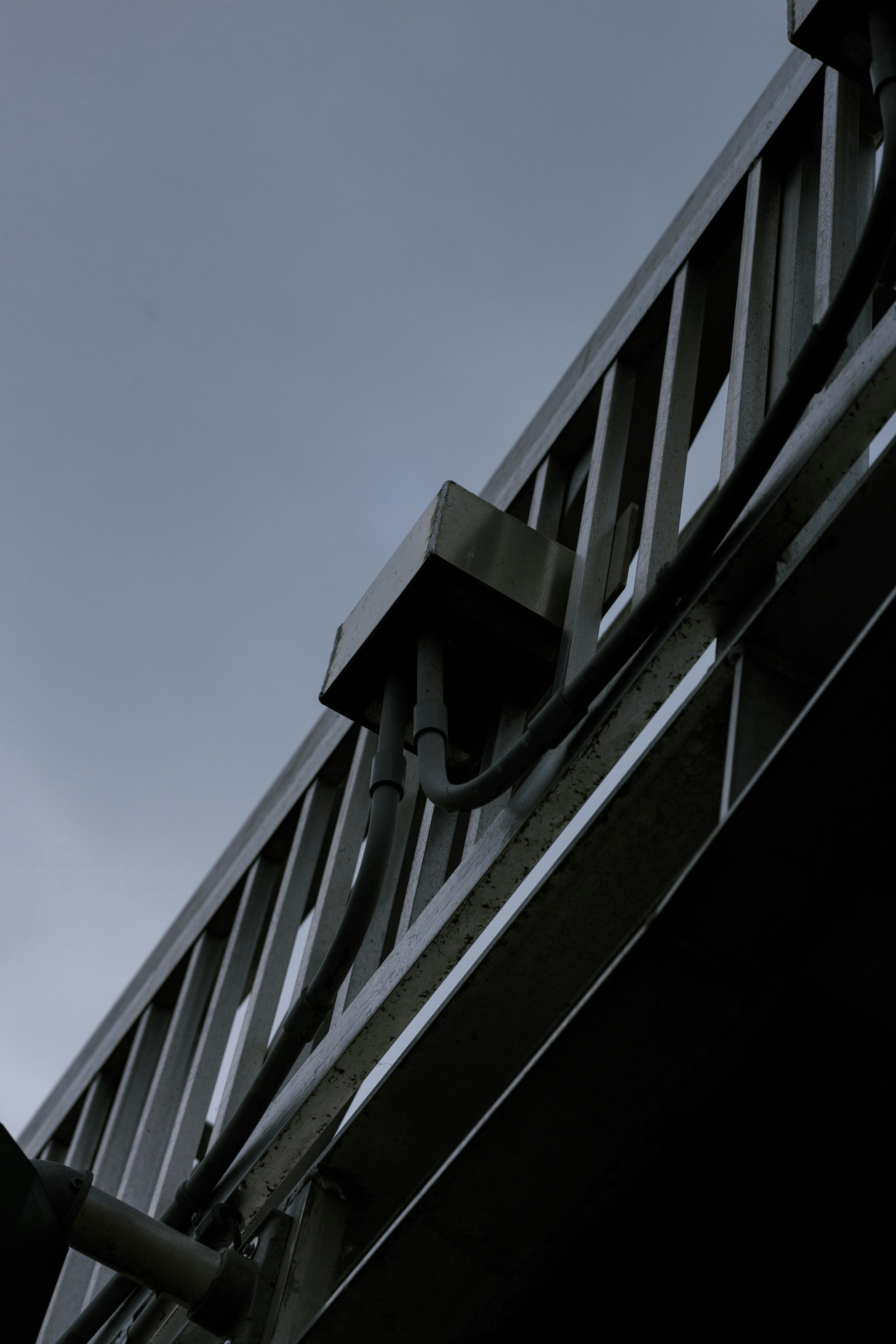 Metal conduits and a junction box against a moody sky, highlighting the often overlooked elements of urban architecture.