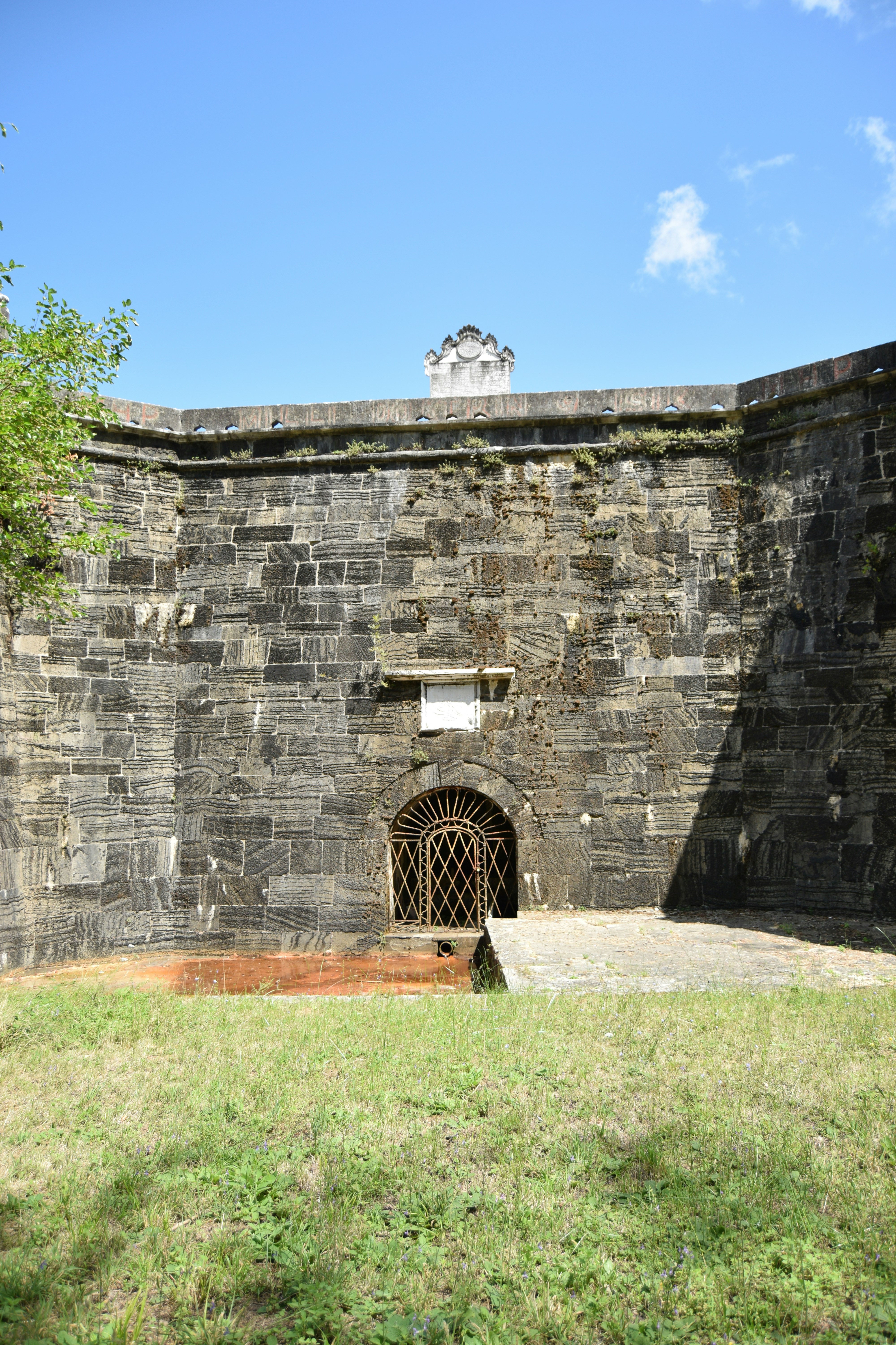 Gatehouse Grit: Iron Grate and Stone Bastion Under a Blue Sky