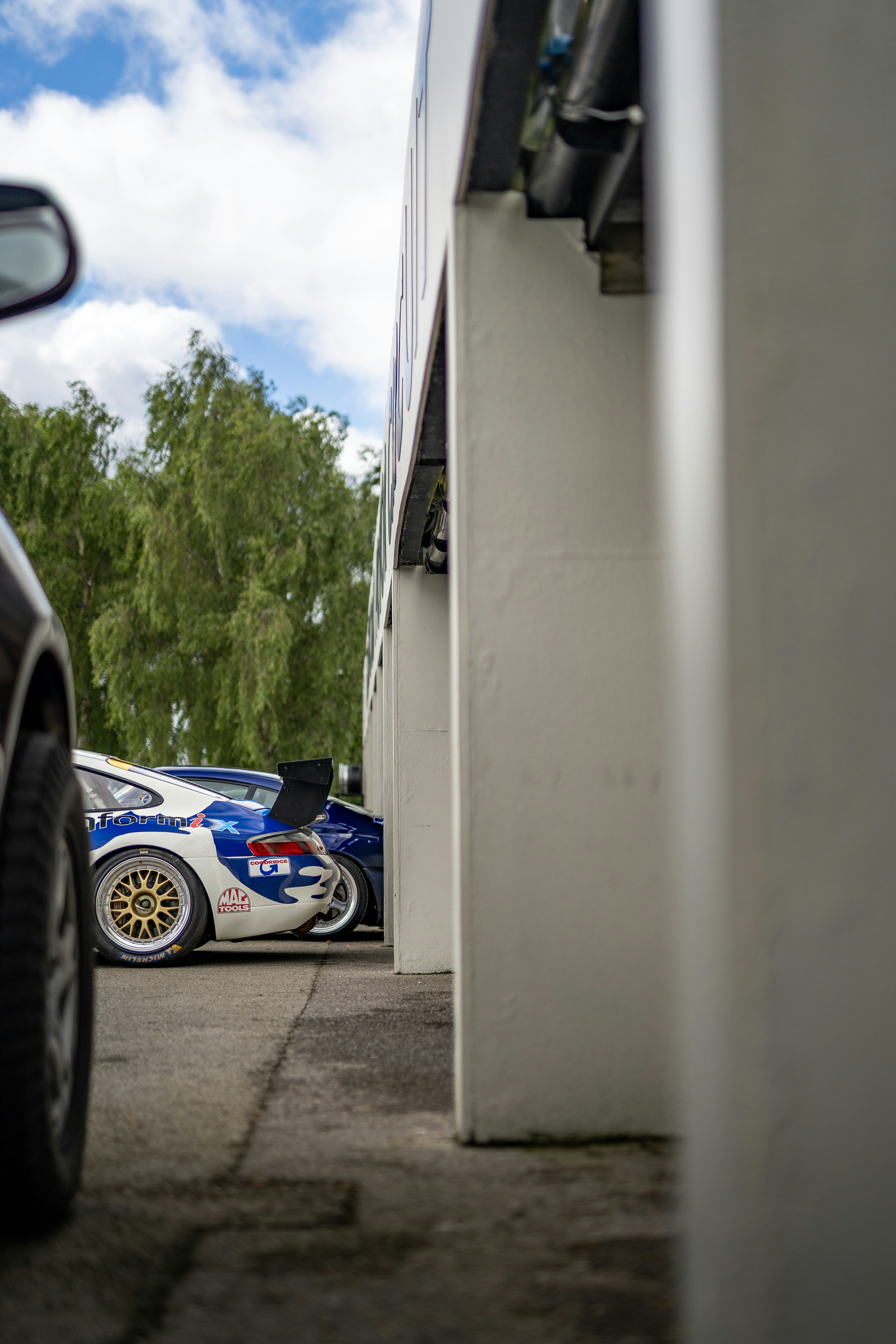 Blue-and-White GT Car Peeks from a Concrete Corridor