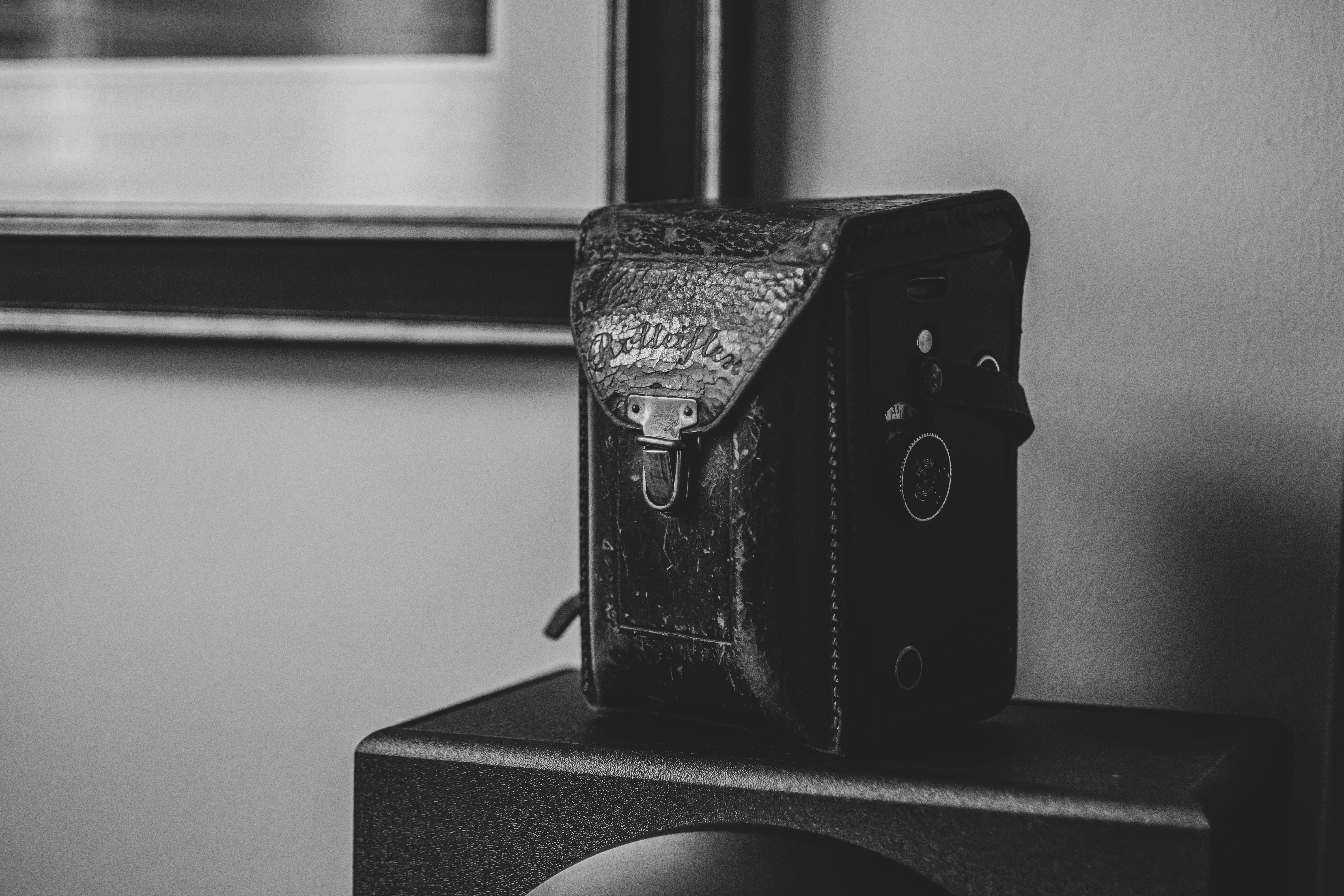 Vintage Leather Box Camera Perched on a Speaker in Quiet Monochrome