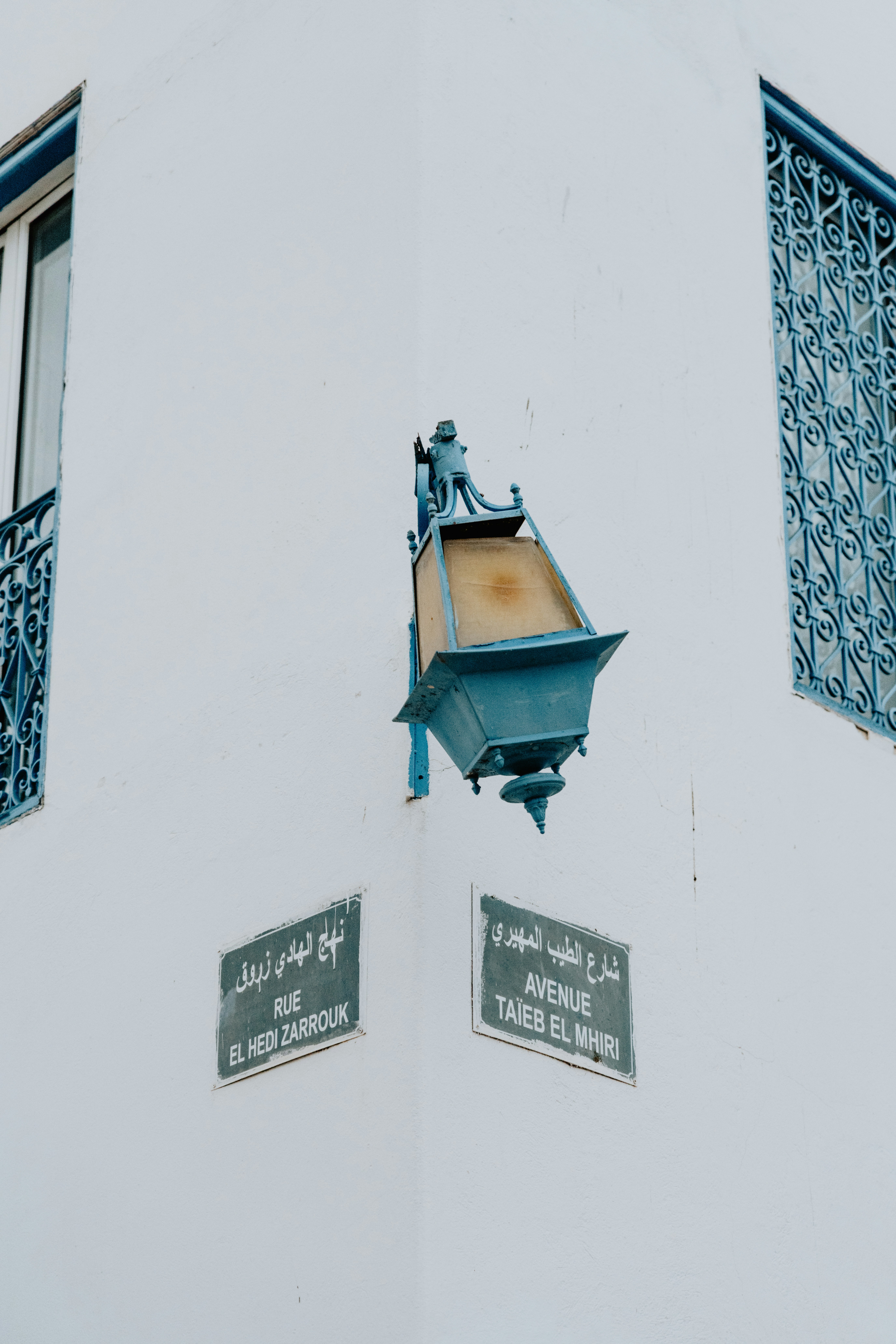Cerulean Lantern on a White-Walled Corner with Bilingual Signage