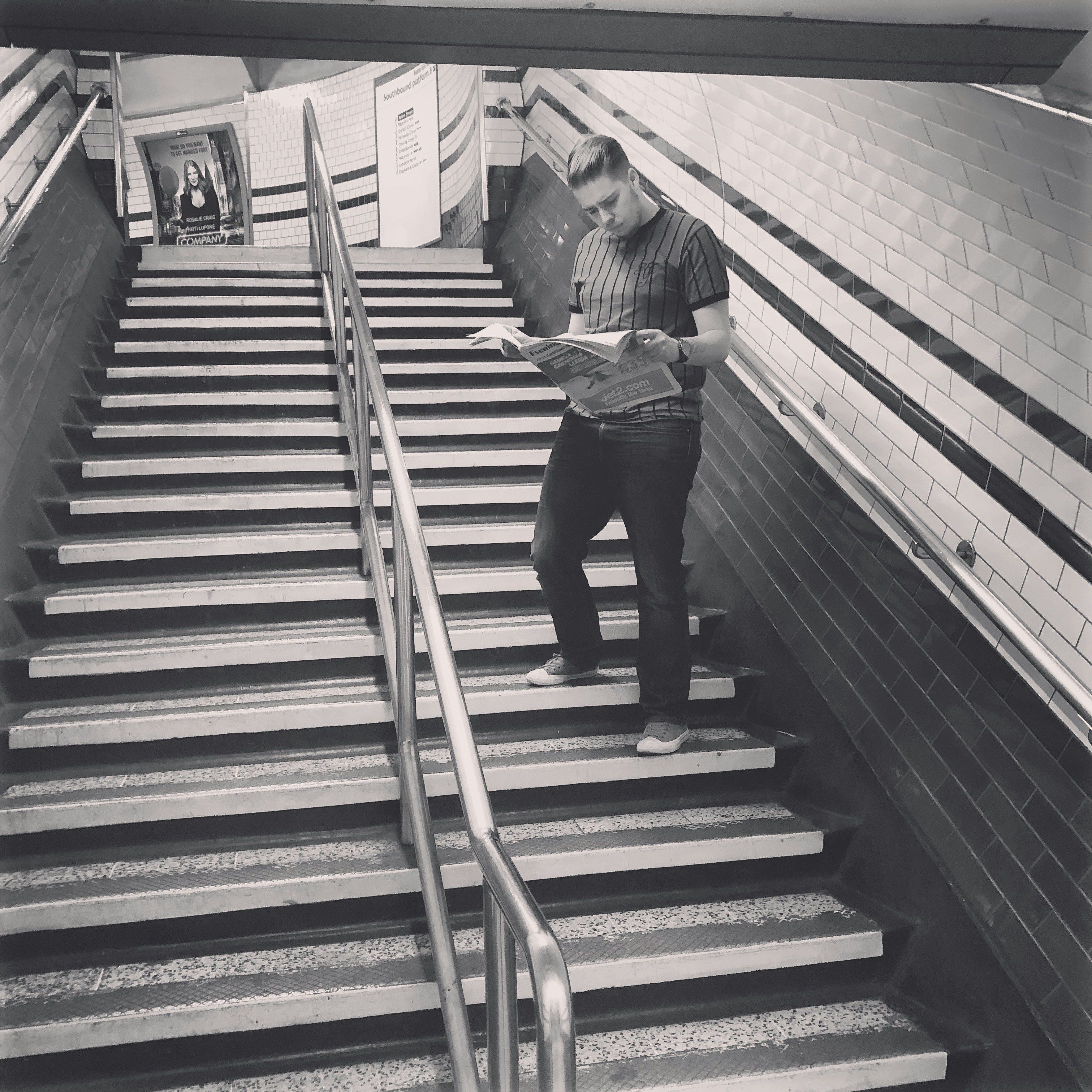 Stairs and Spotlight Reader: a man pauses mid-commute to skim the morning paper