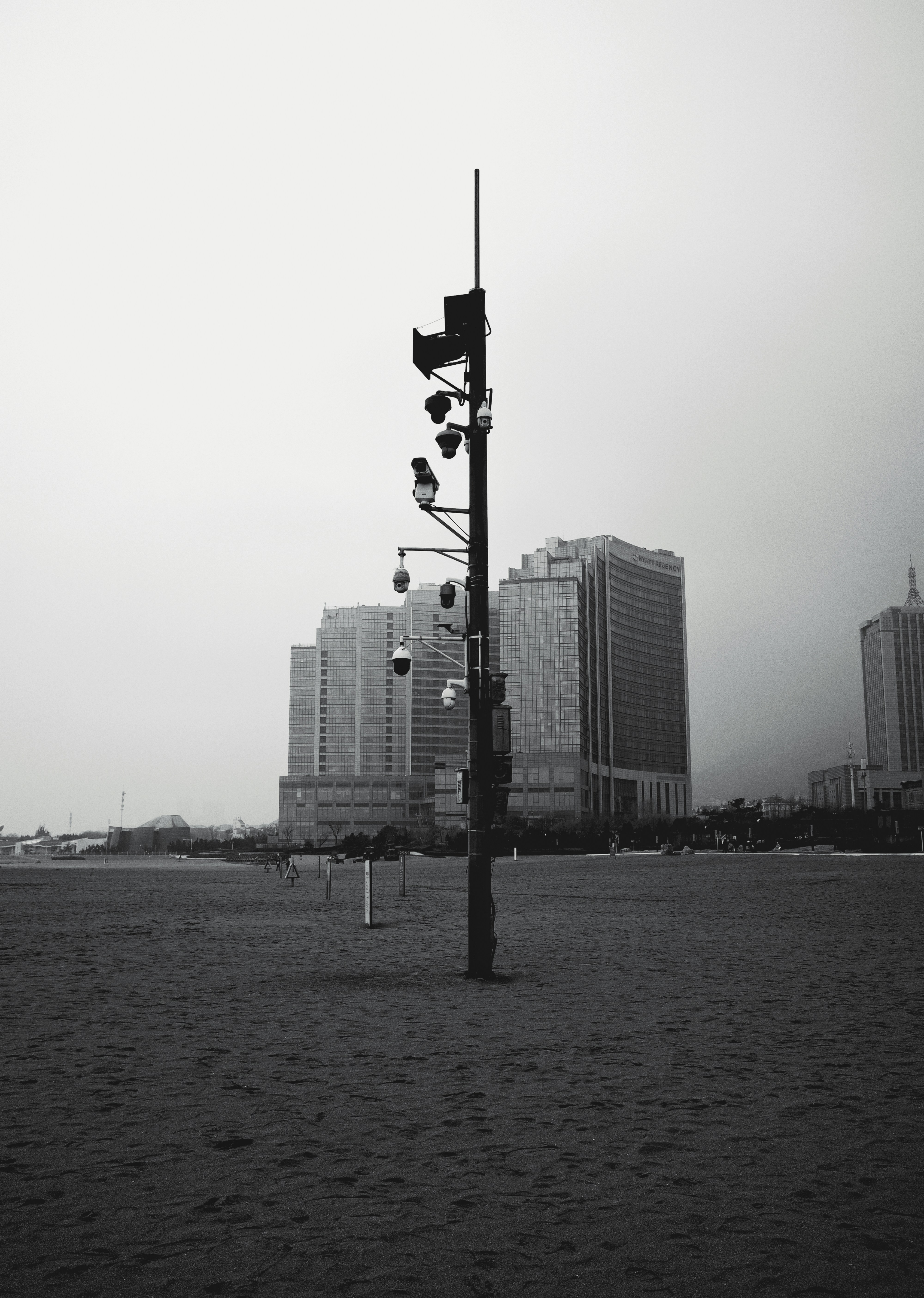 Vertical Beacon at the Edge: Windswept Beach Meets a Distant Skyline