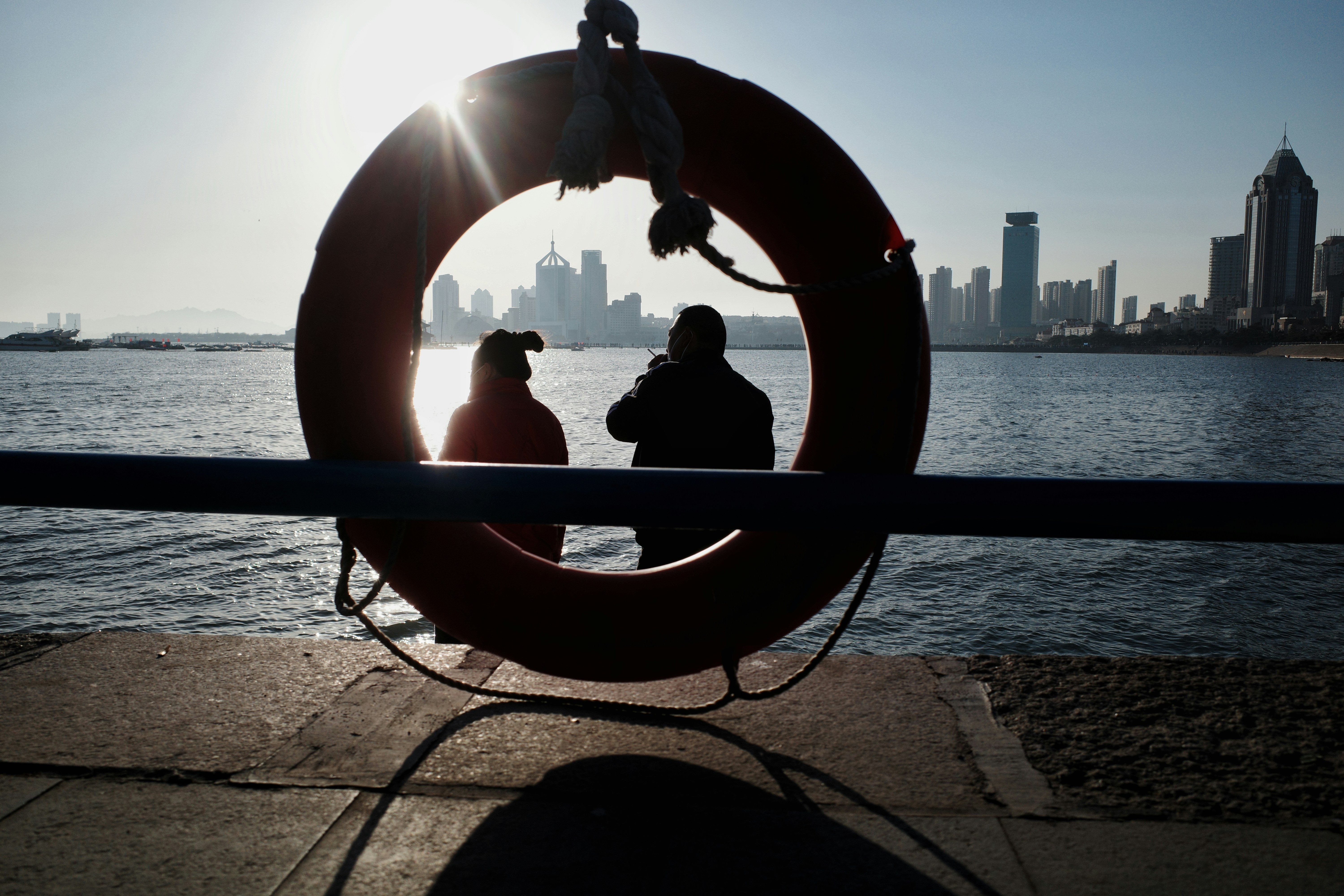 A couple of people sitting on a bench near a body of water