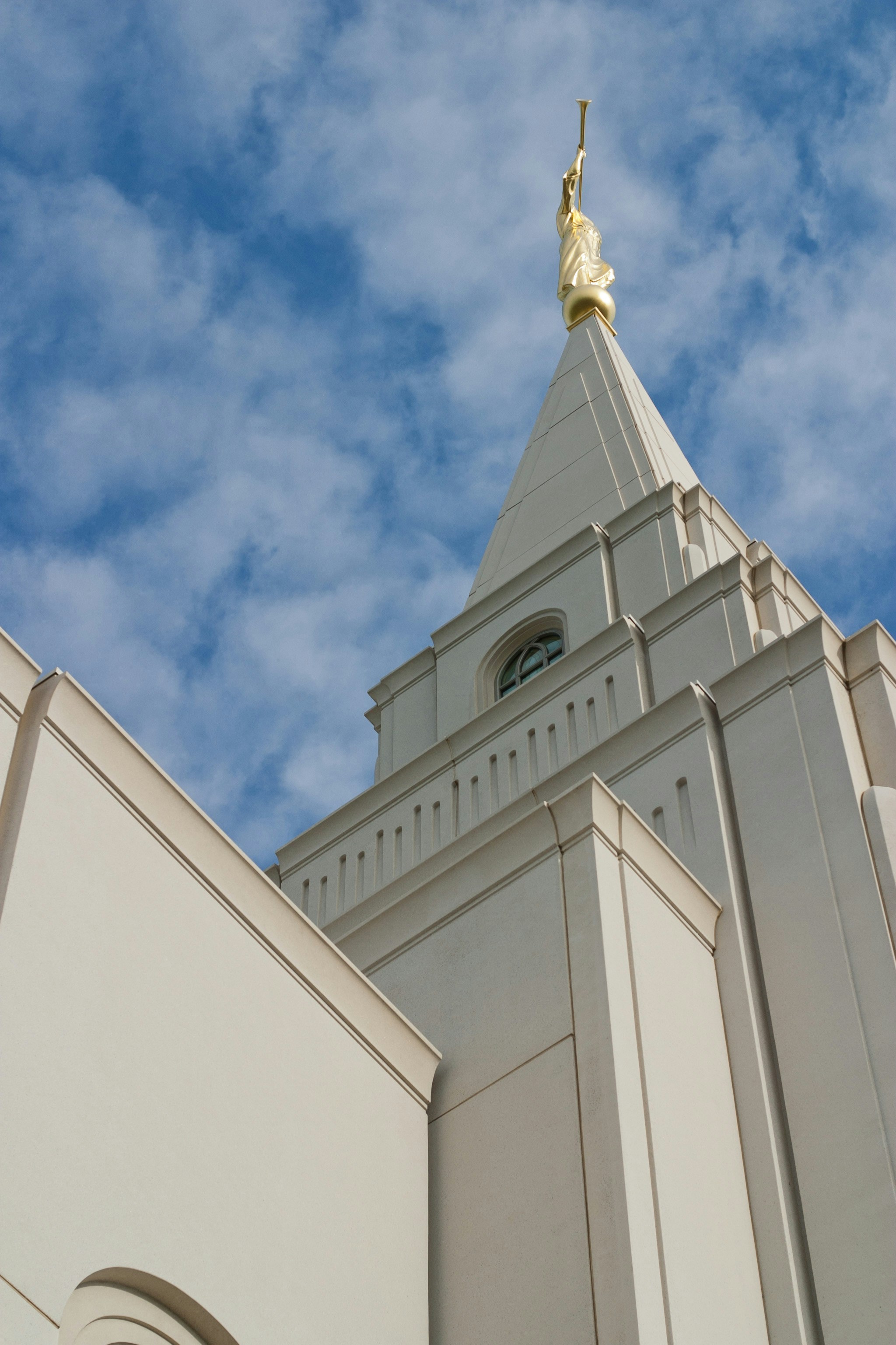 A pale church spire rises against a bright blue sky, emphasizing geometric architecture and clean lines.