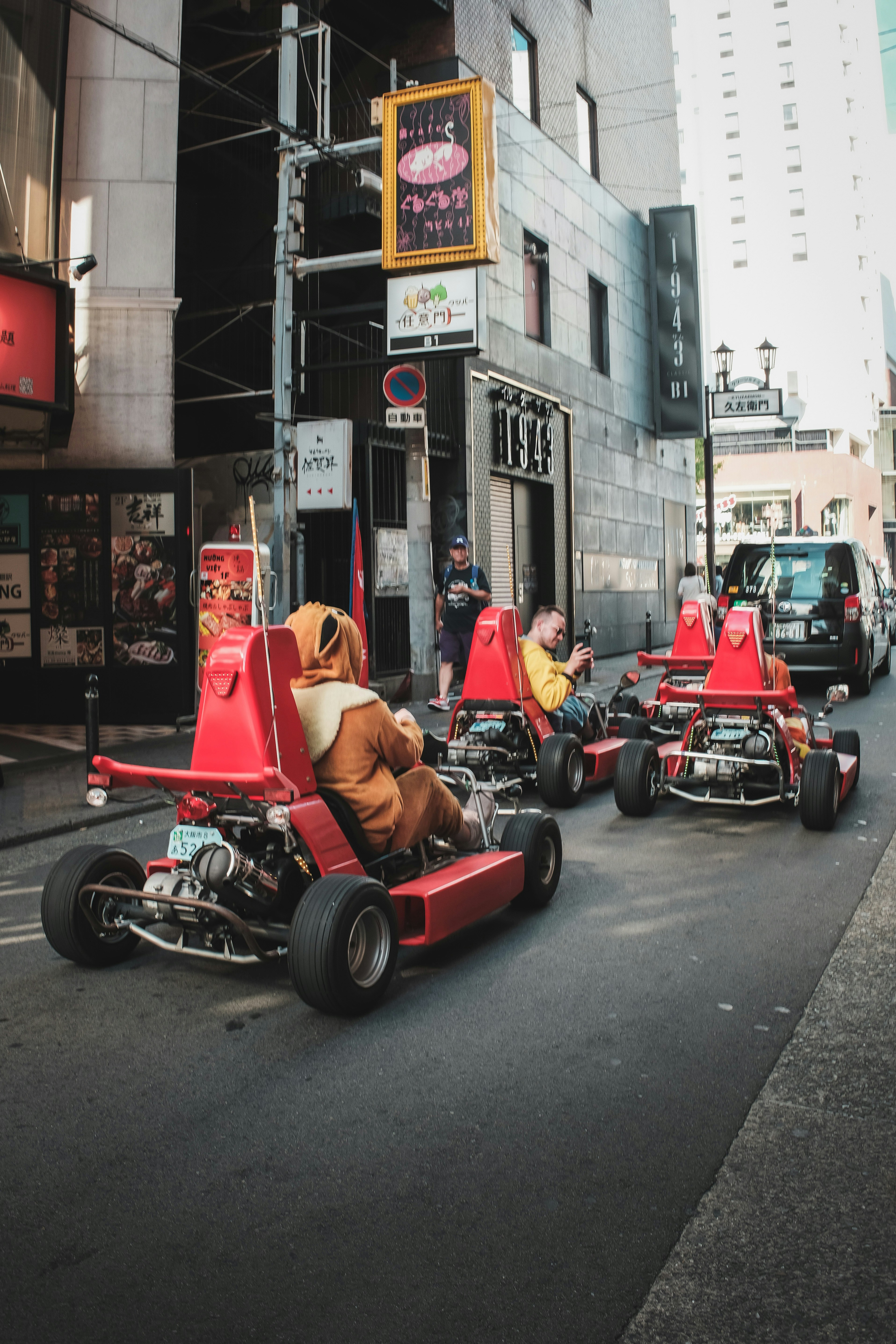 Convoy of Red Go-Karts Races Down a Narrow Tokyo Street
