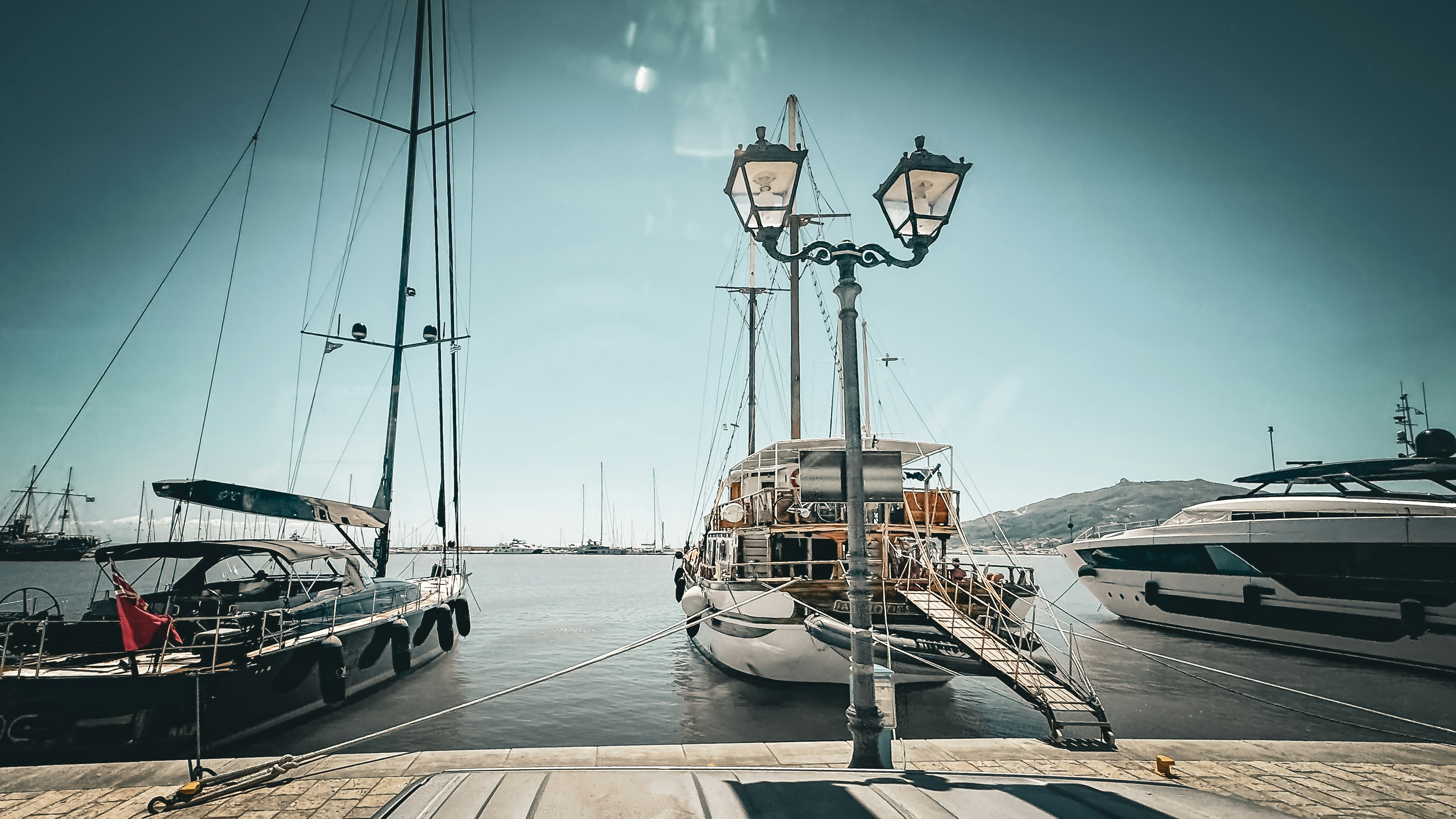 Docked yachts under a clear blue sky with a vintage-style lamp post in the foreground.