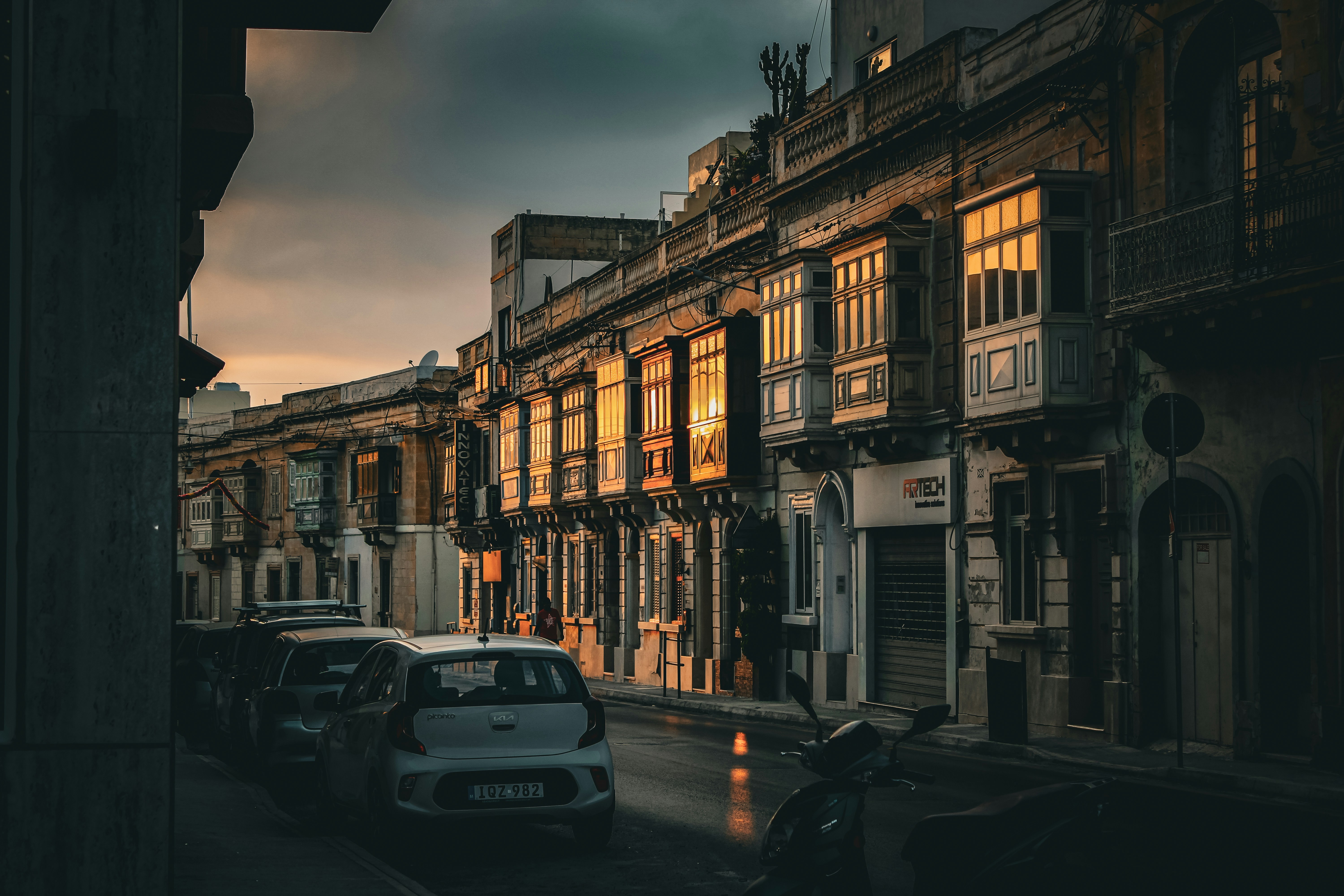 Sunset light reflecting on a row of historic buildings along a quiet street.