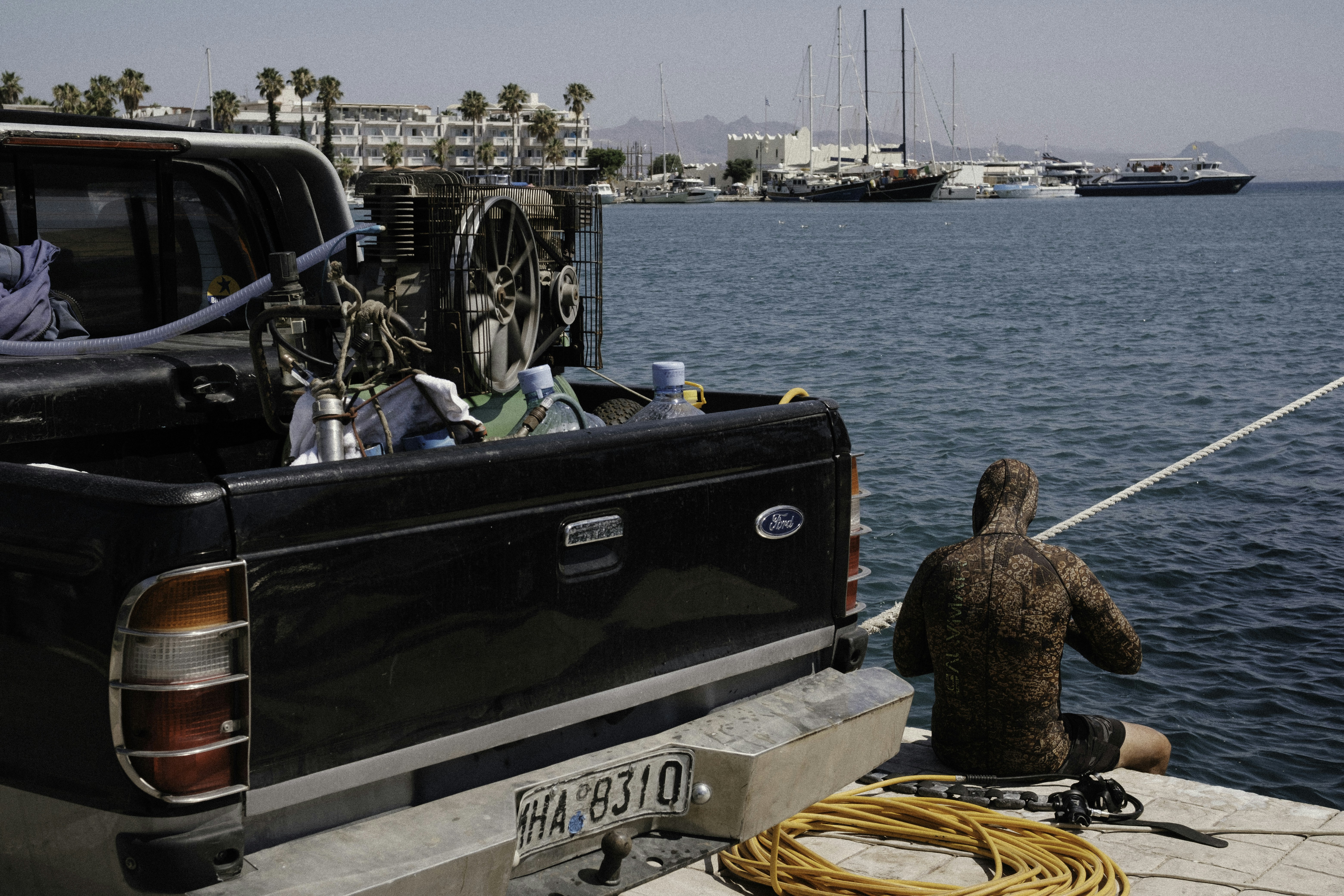 A man sitting on the back of a truck next to a body of water