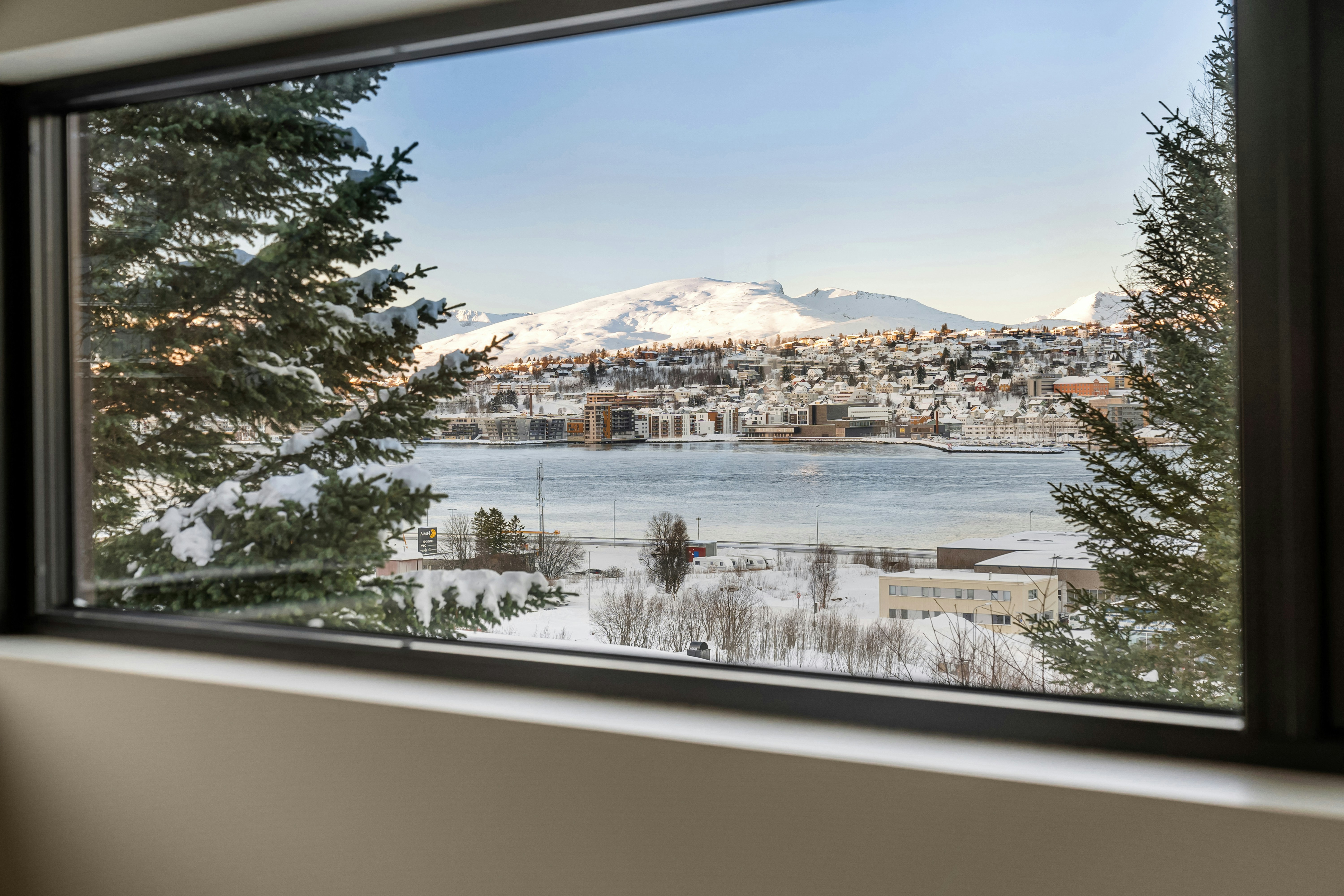 Framed Winter on the Fjord: Snow-Blanketed Town Beyond the Window