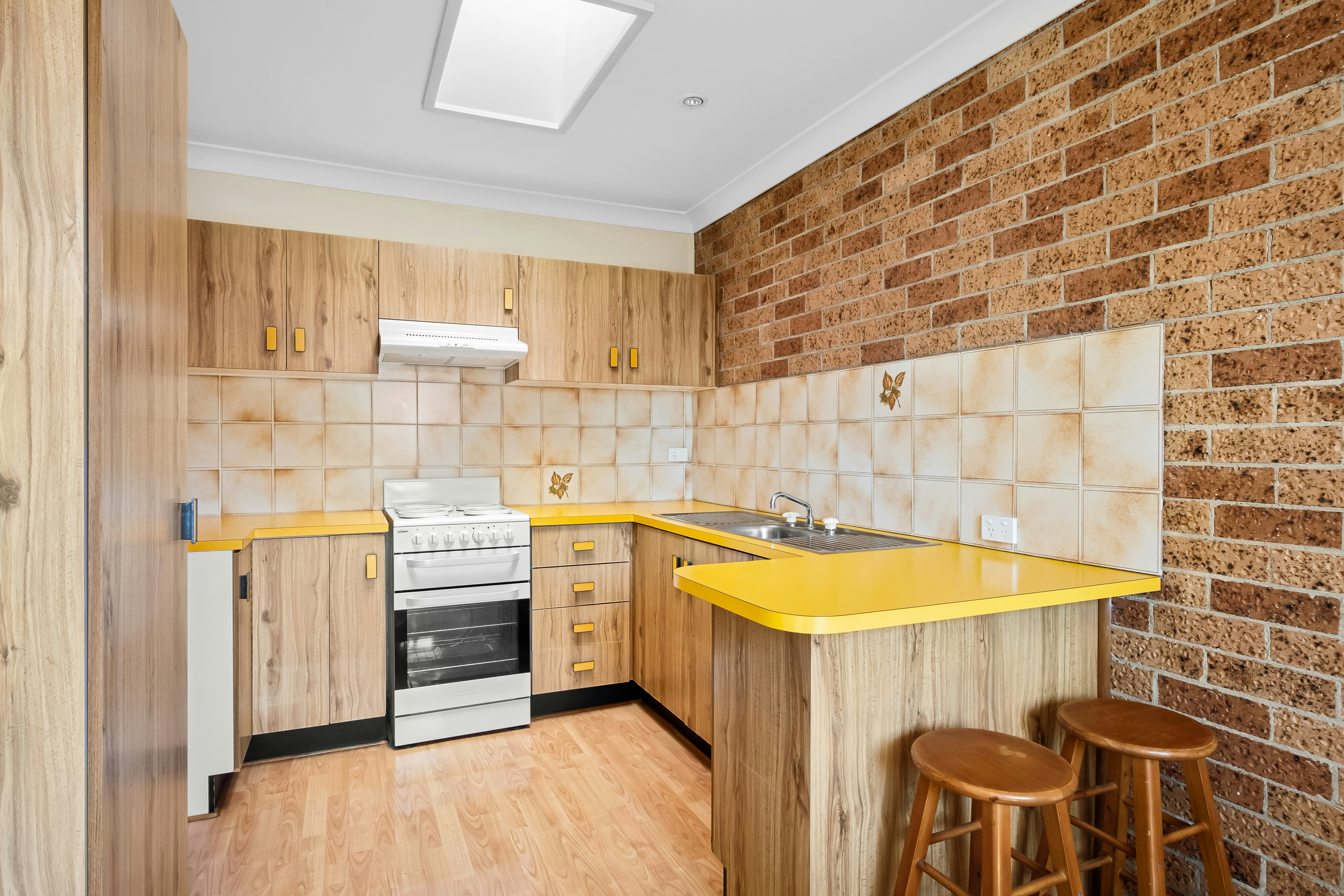 A kitchen with a yellow counter top next to a brick wall photo – Free ...