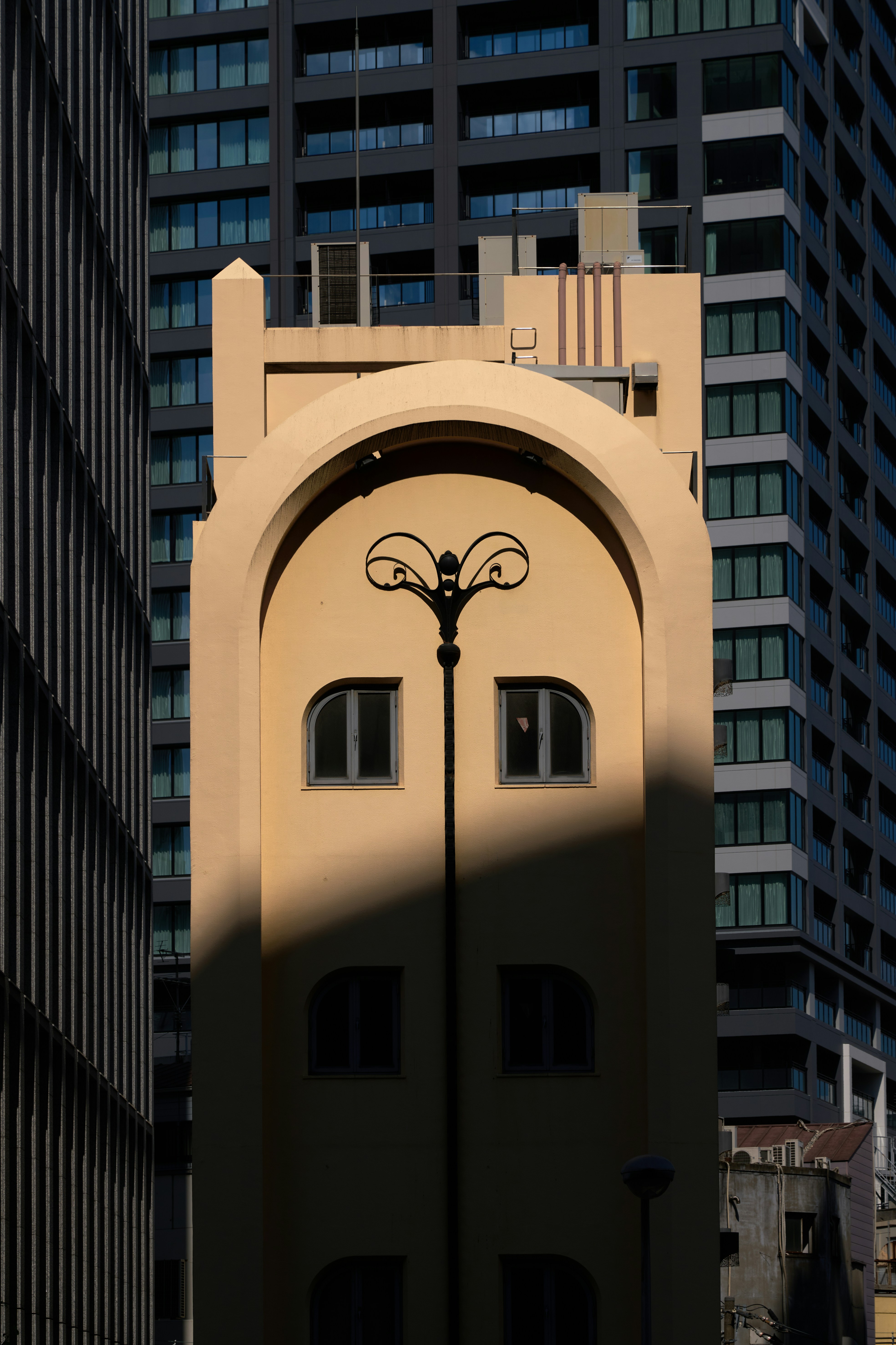 Beige Arch Amid Glass Giants: Geometry in Shadow