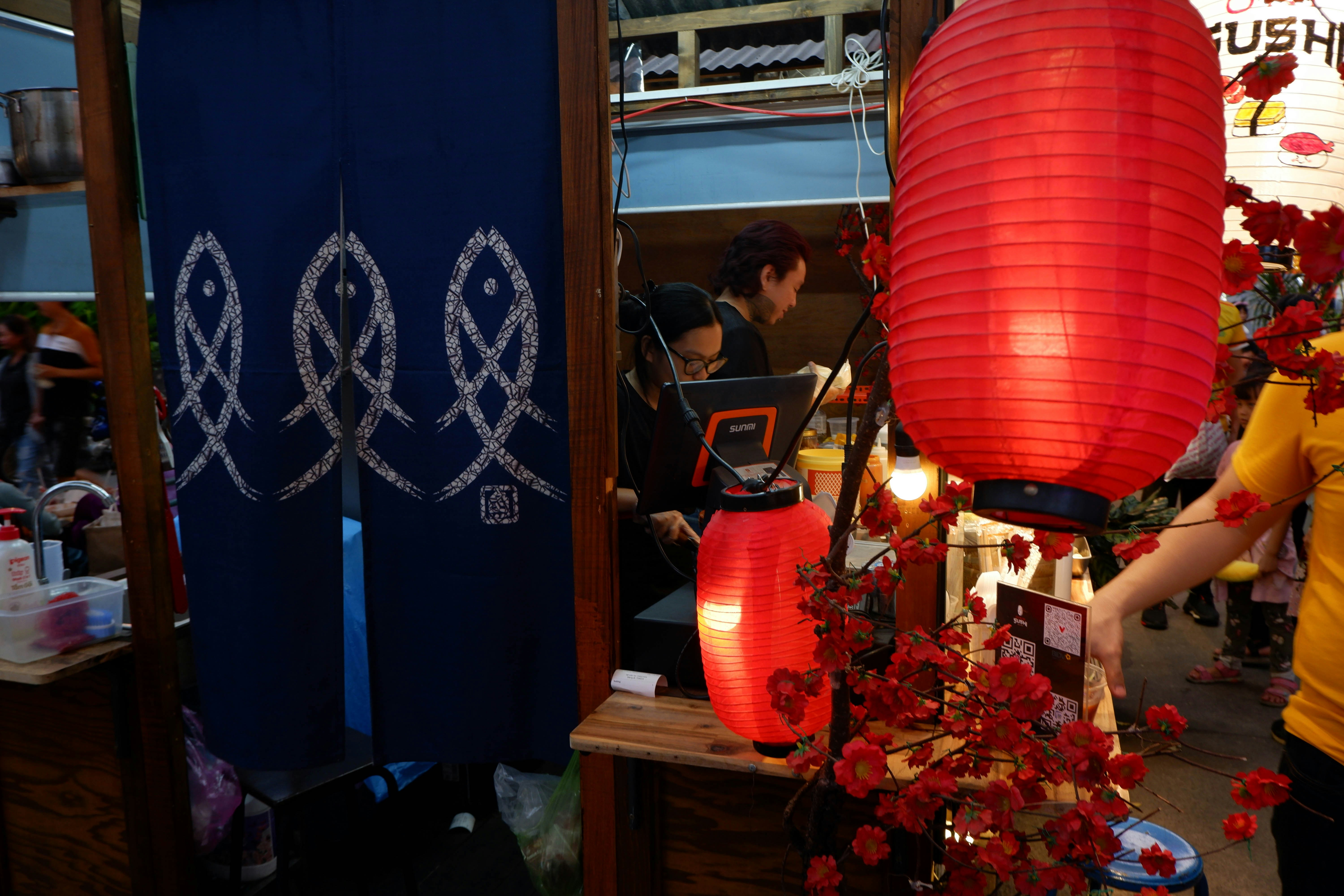 Crimson Lanterns and Blue Drapes at a Night Market Booth