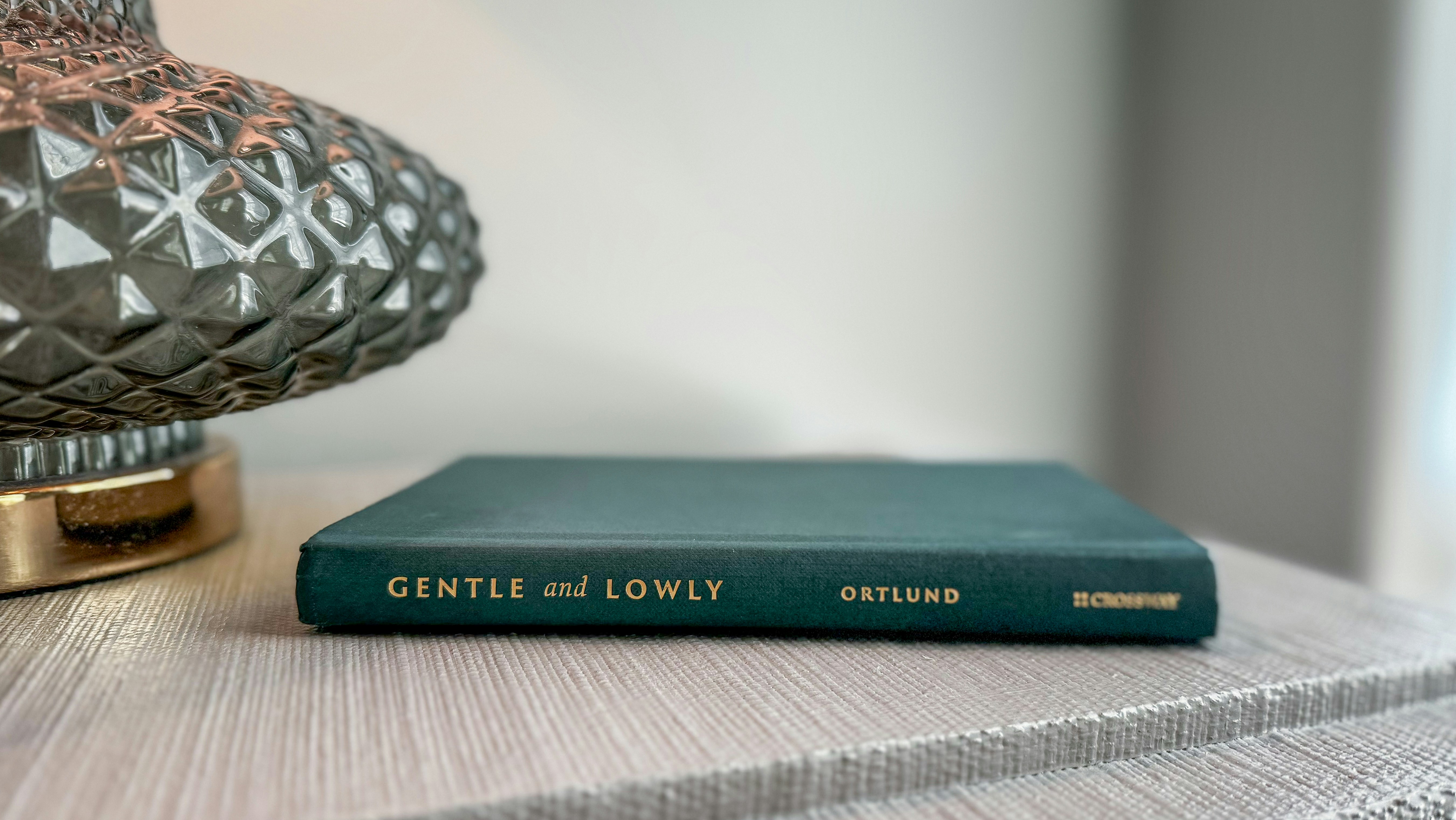 Quiet Shelf Moment: A Green Book Resting Beside a Dimpled Lamp