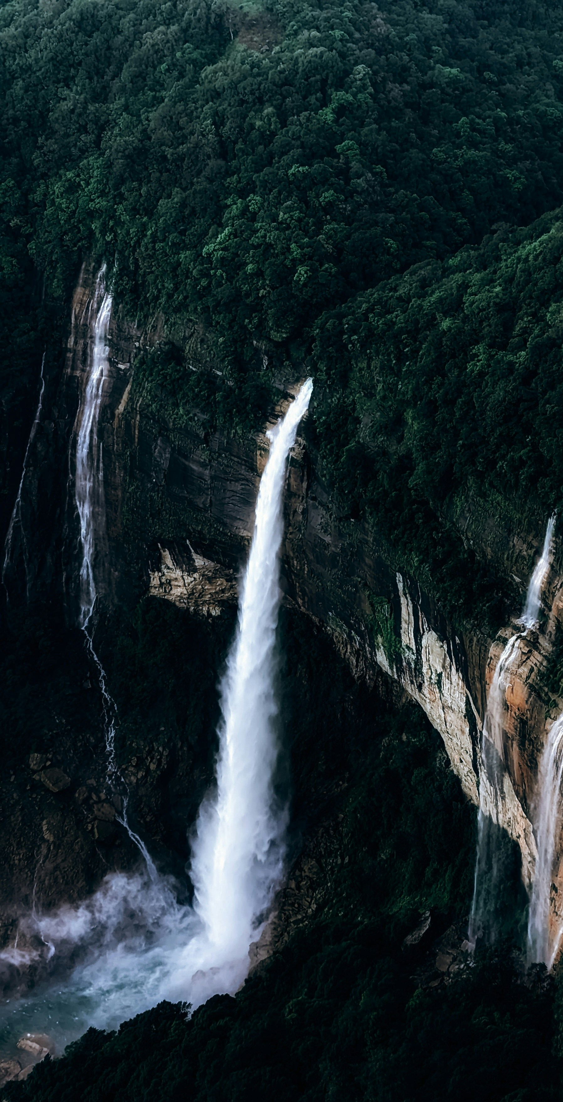 A large waterfall with water falling from it's sides photo – Free ...